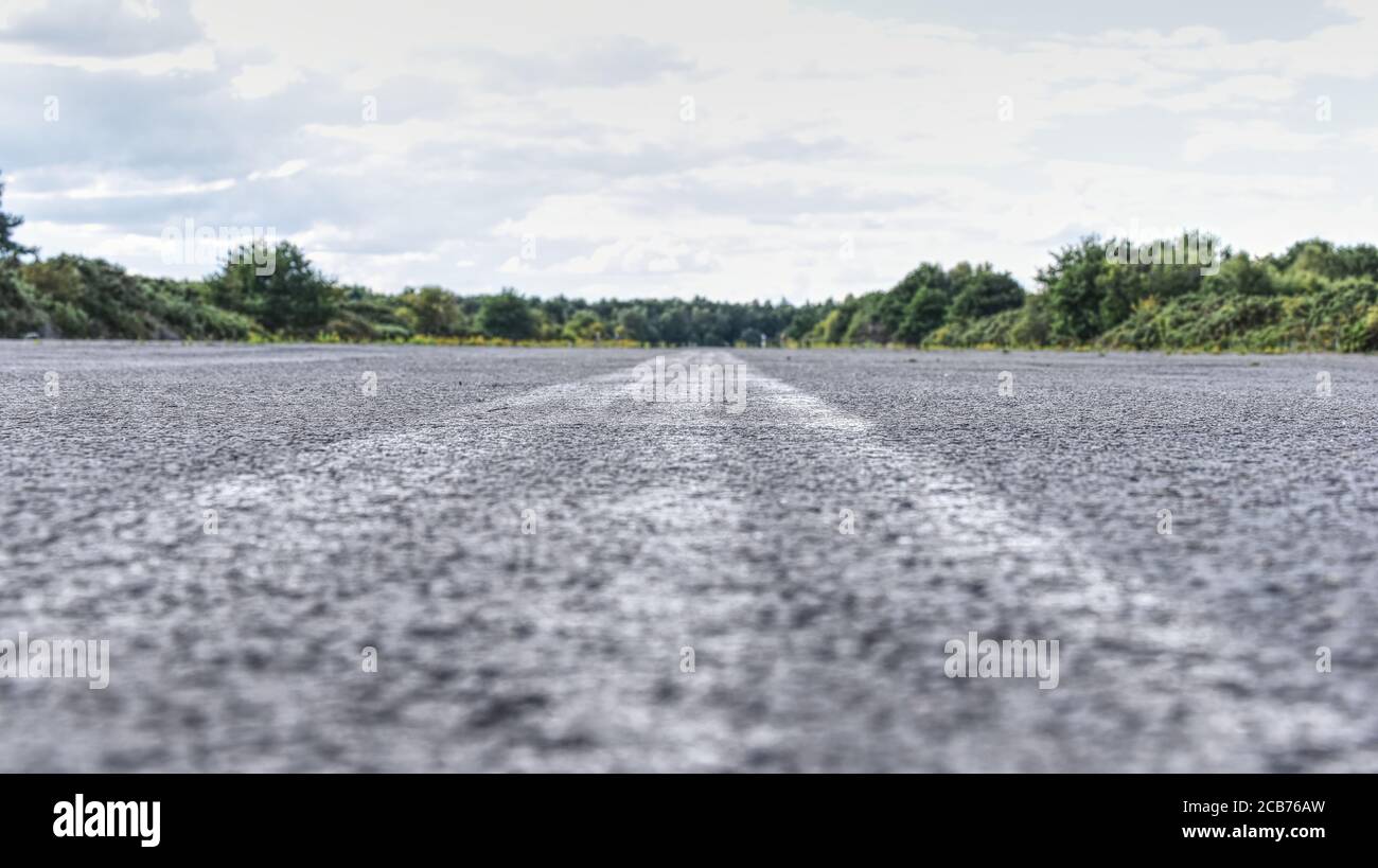 A faded white line on a disused runway at Blackbushe, Yateley Common in ...