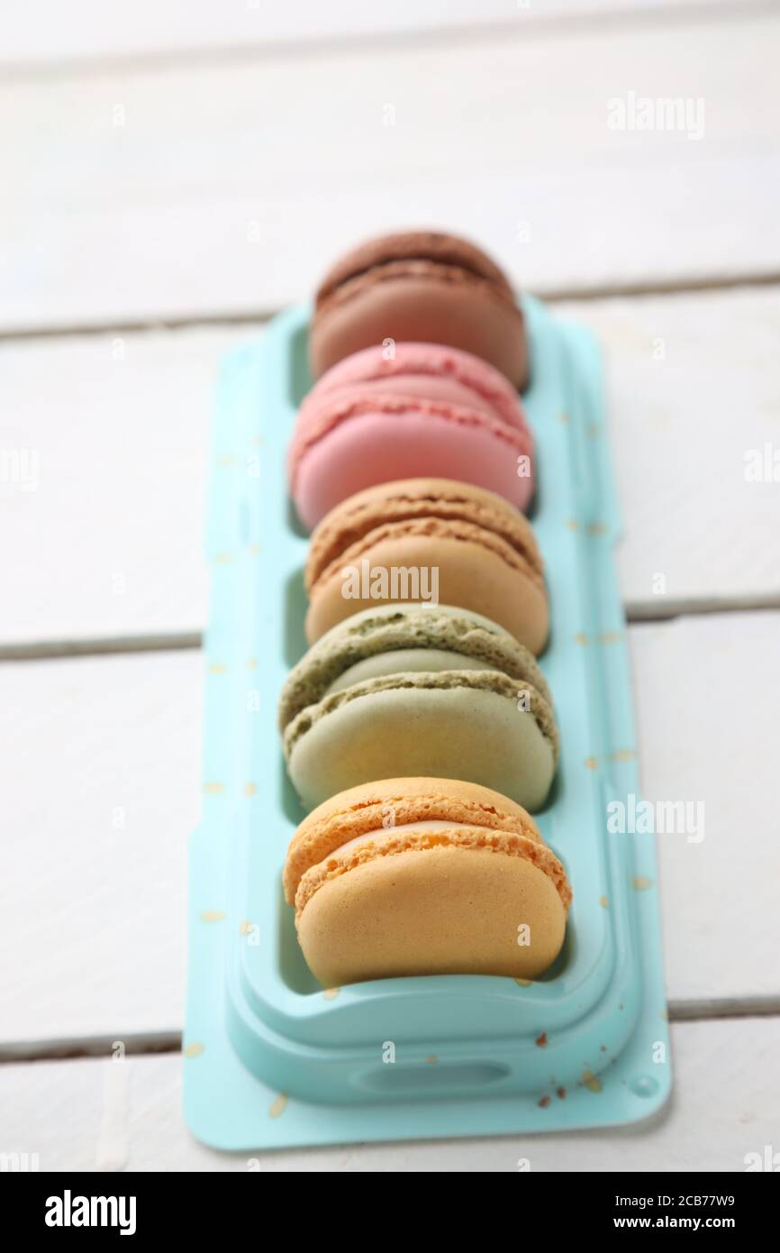 Vertical closeup of tasty and colorful macarons lined vertically on a ...