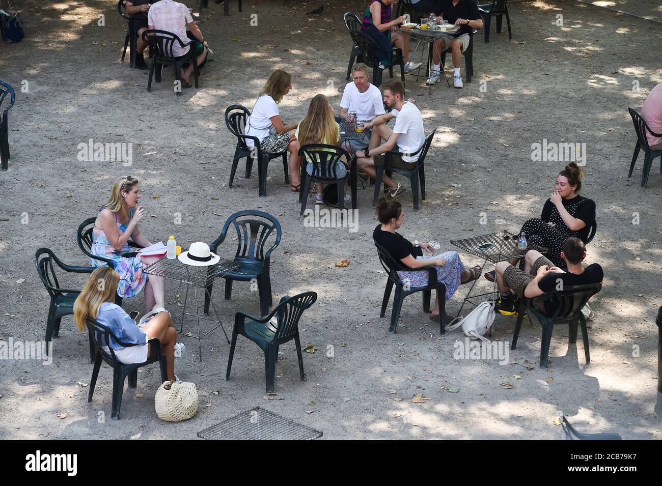 People sit in the shade as they enjoy lunch in the hot weather on the ...