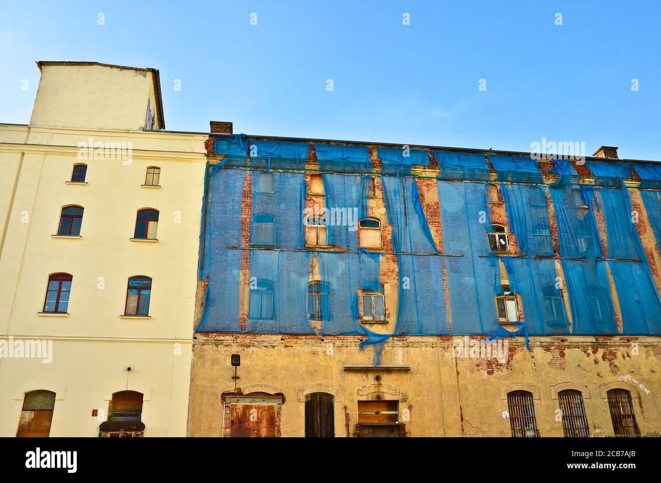 The facade of an old ruinous building is mantled with some blue ...