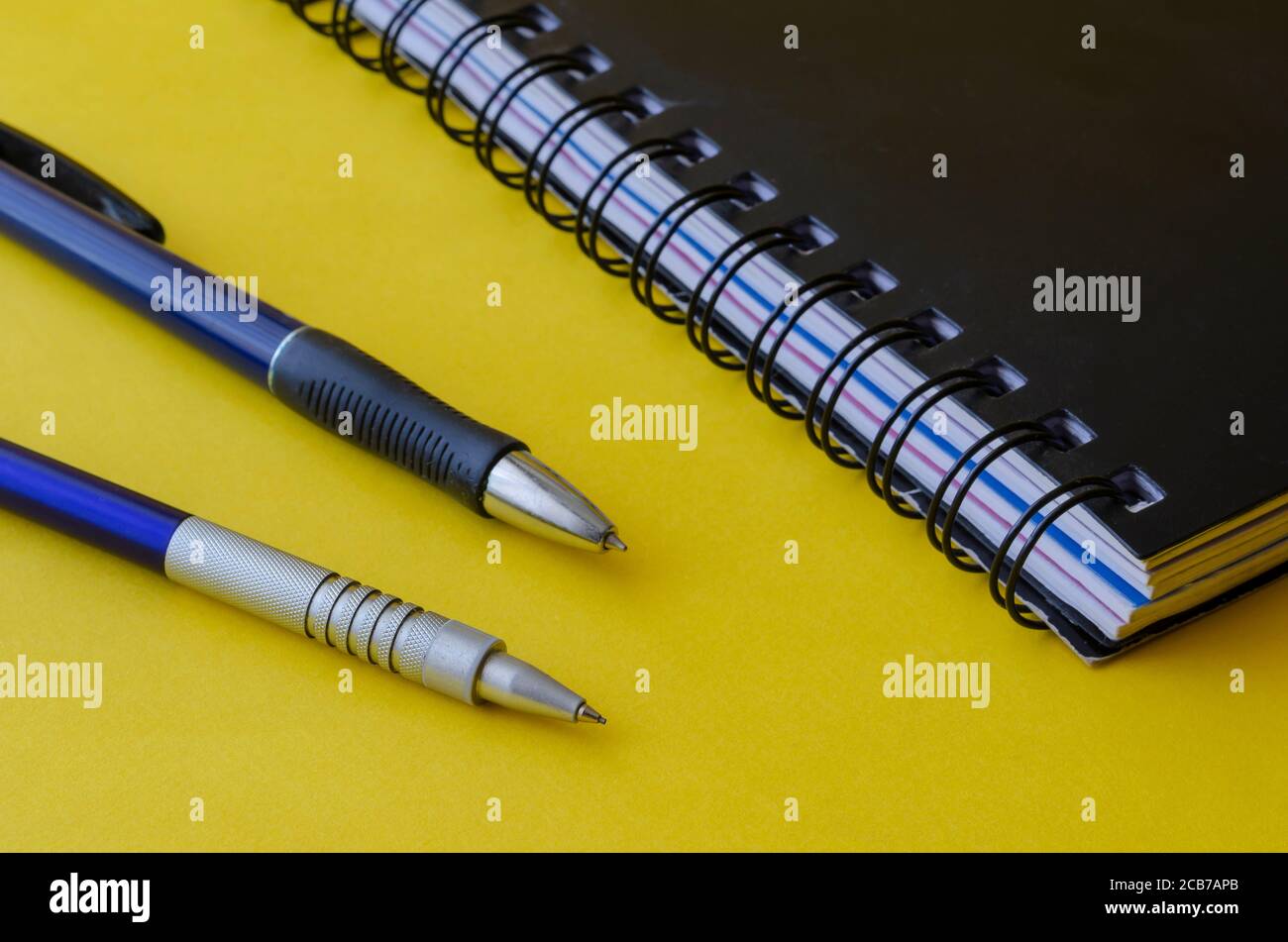 Notebook with spring and two pens on yellow background. Business ...