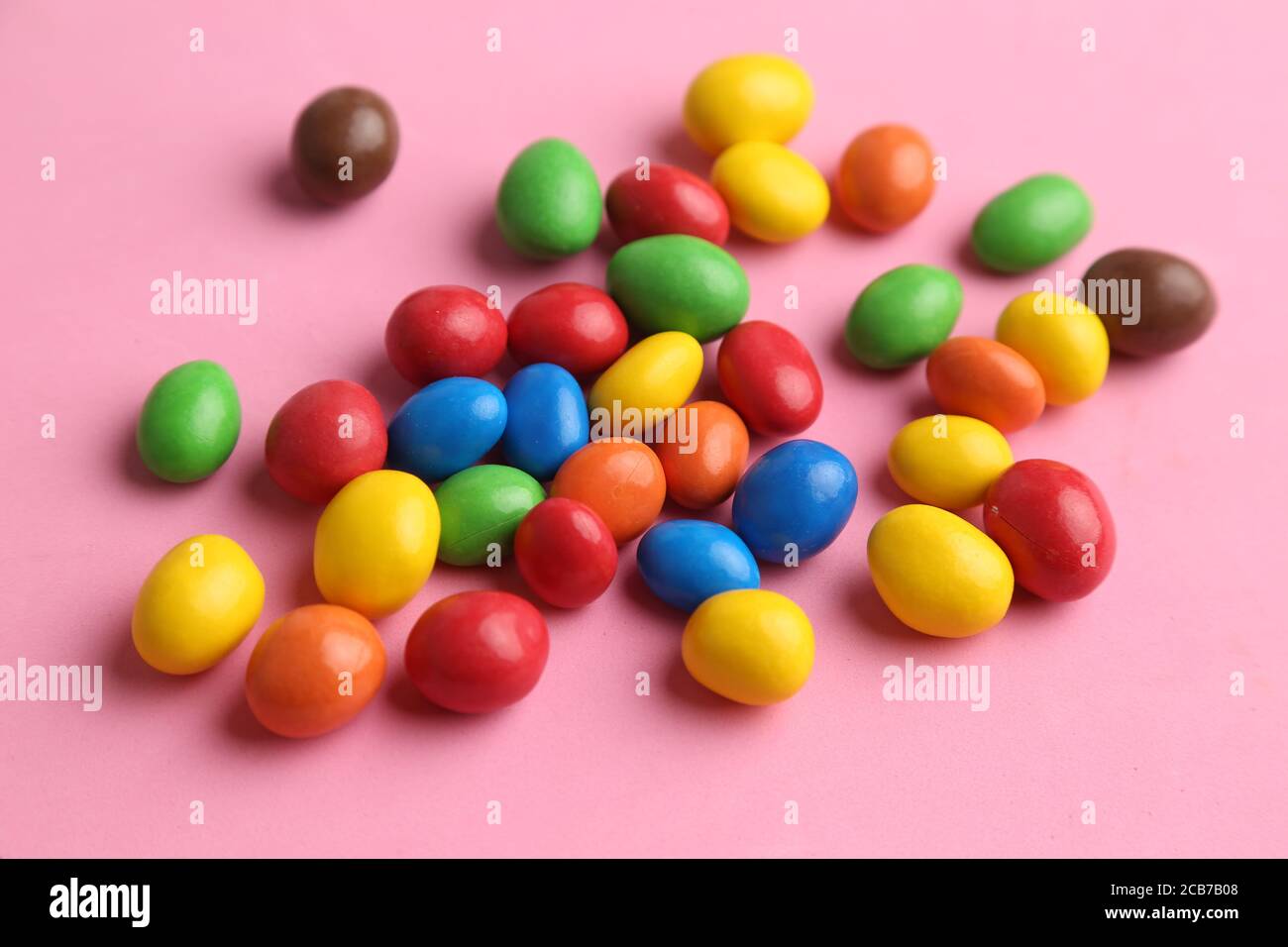 Closeup shot of colorful candy balls isolated scattered on a pink ...