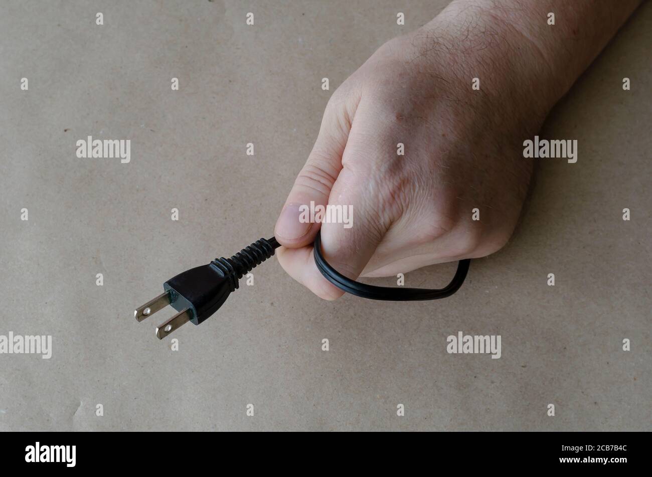 Hand of an adult Caucasian male is holding black electric plug. DC ...