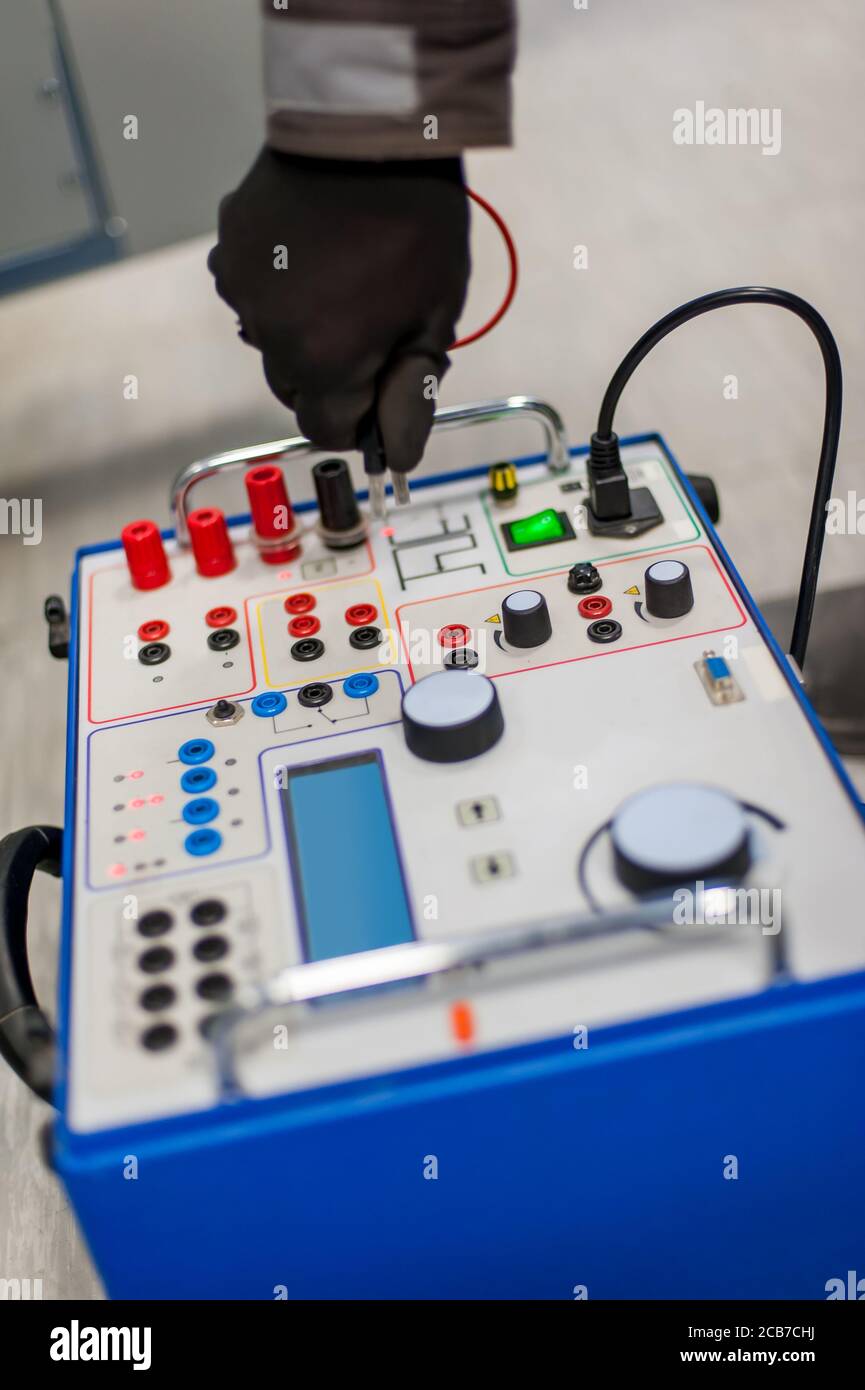 Electrician engineer tests system with relay test set equipment. Relay ...