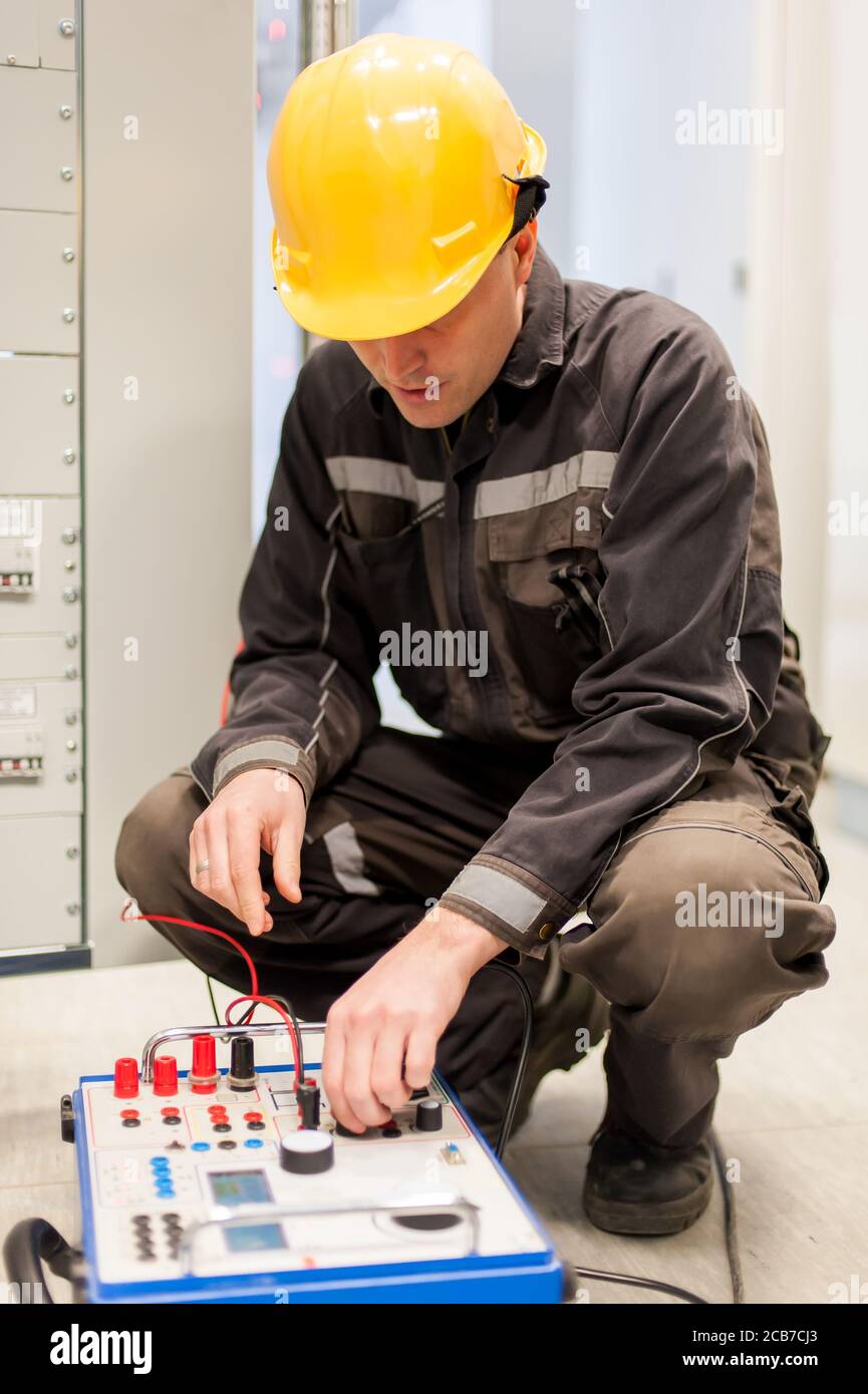 Electrician engineer tests system with relay test set equipment. Relay ...