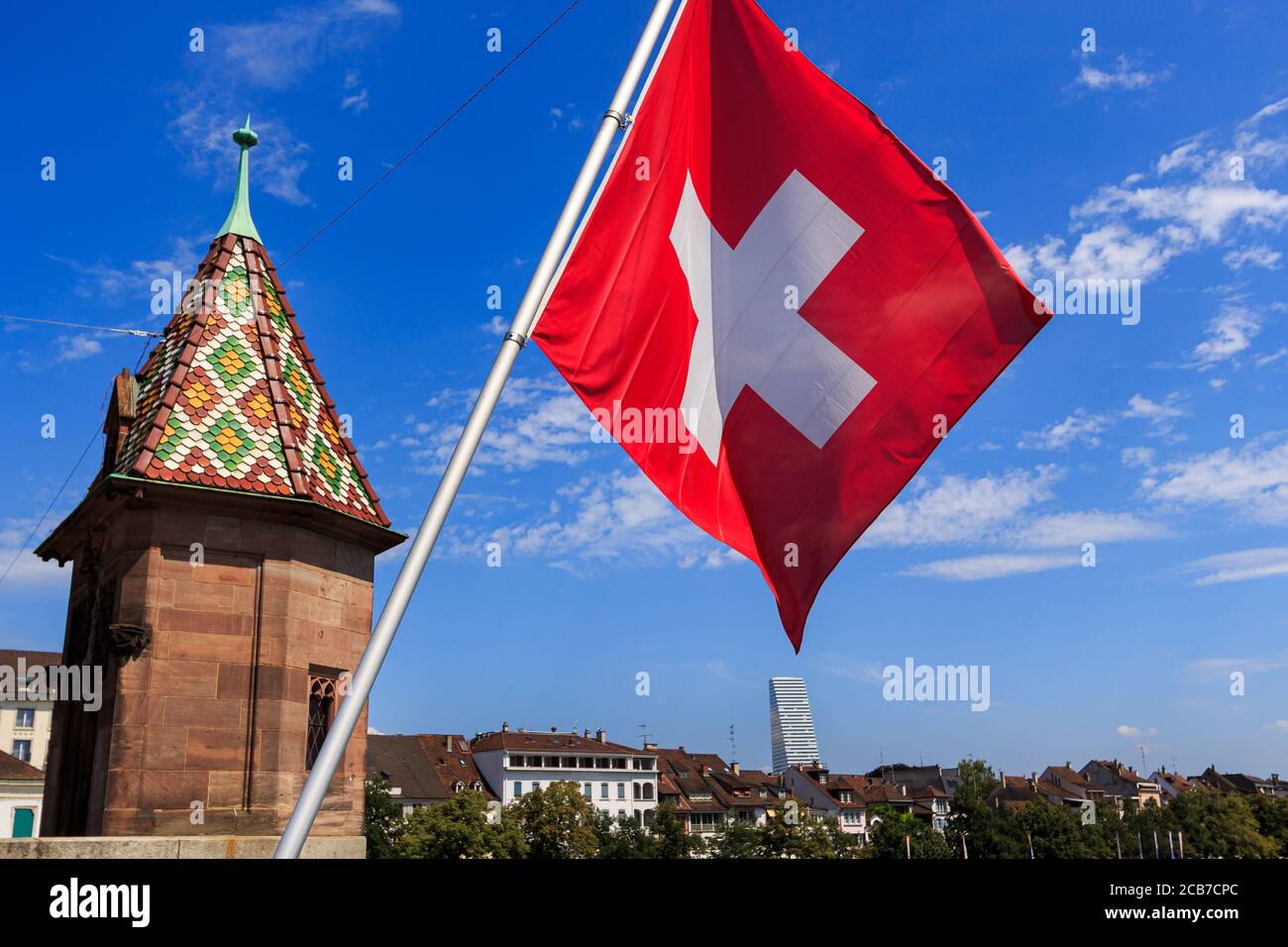 Swiss flag on a bridge in Basel (Switzerland), tower and city skyline ...