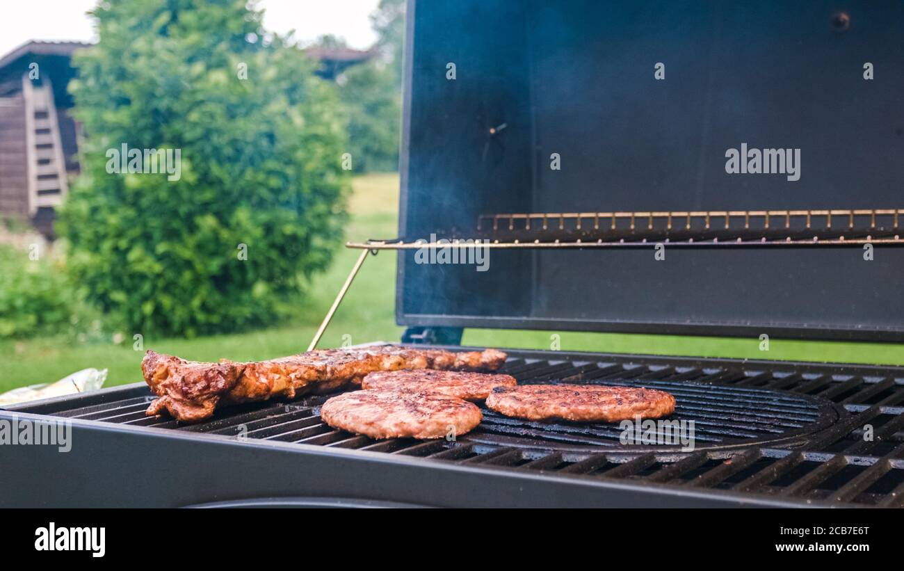 Home barbecue with charcoal in the backyard grilling steaks and other ...