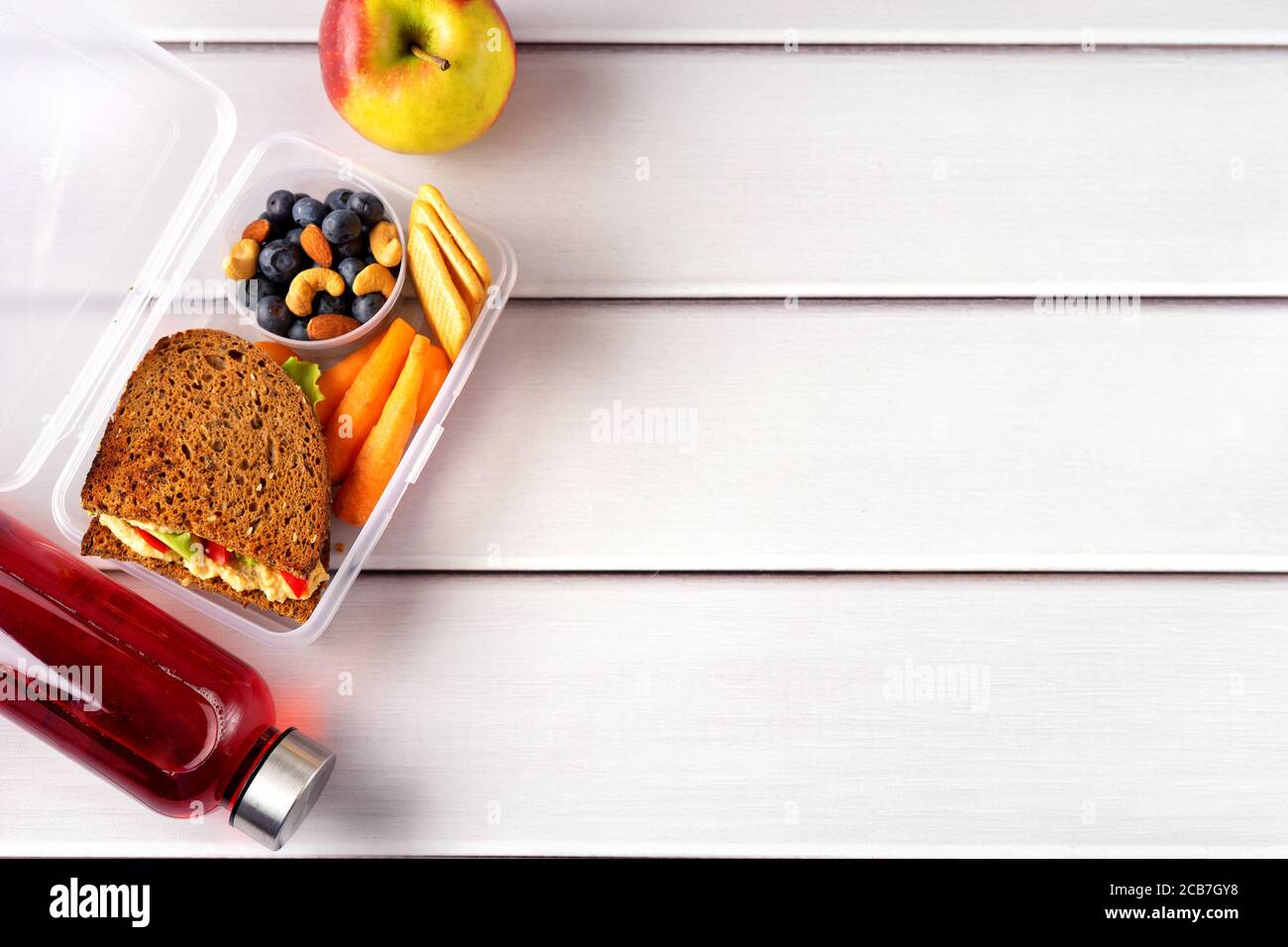Top view of a healthy school lunch in a box, apple and bottle with red ...