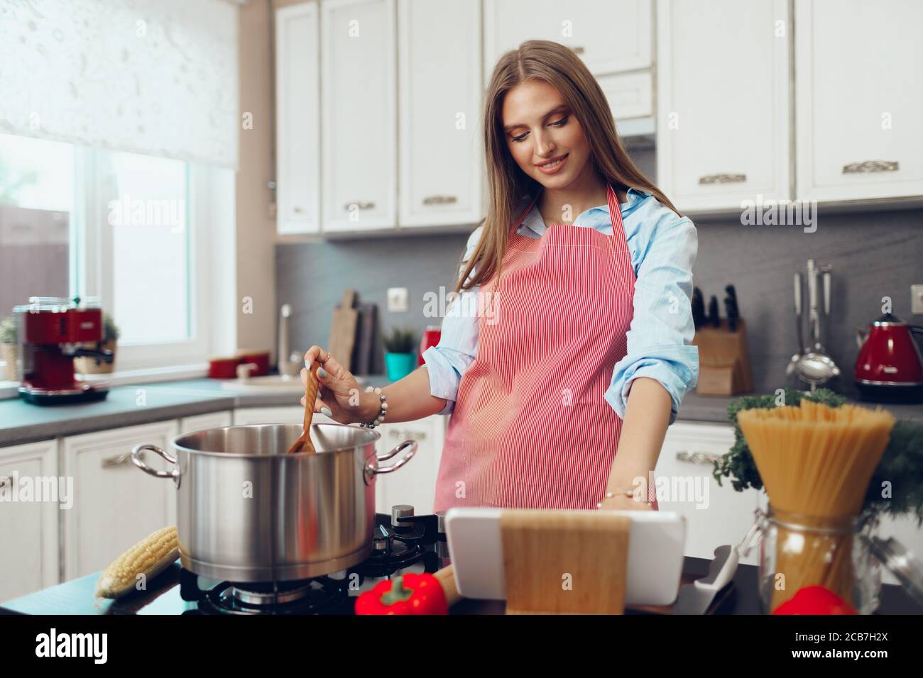 Nice young woman cooking something by the stove in her kitchen Stock ...