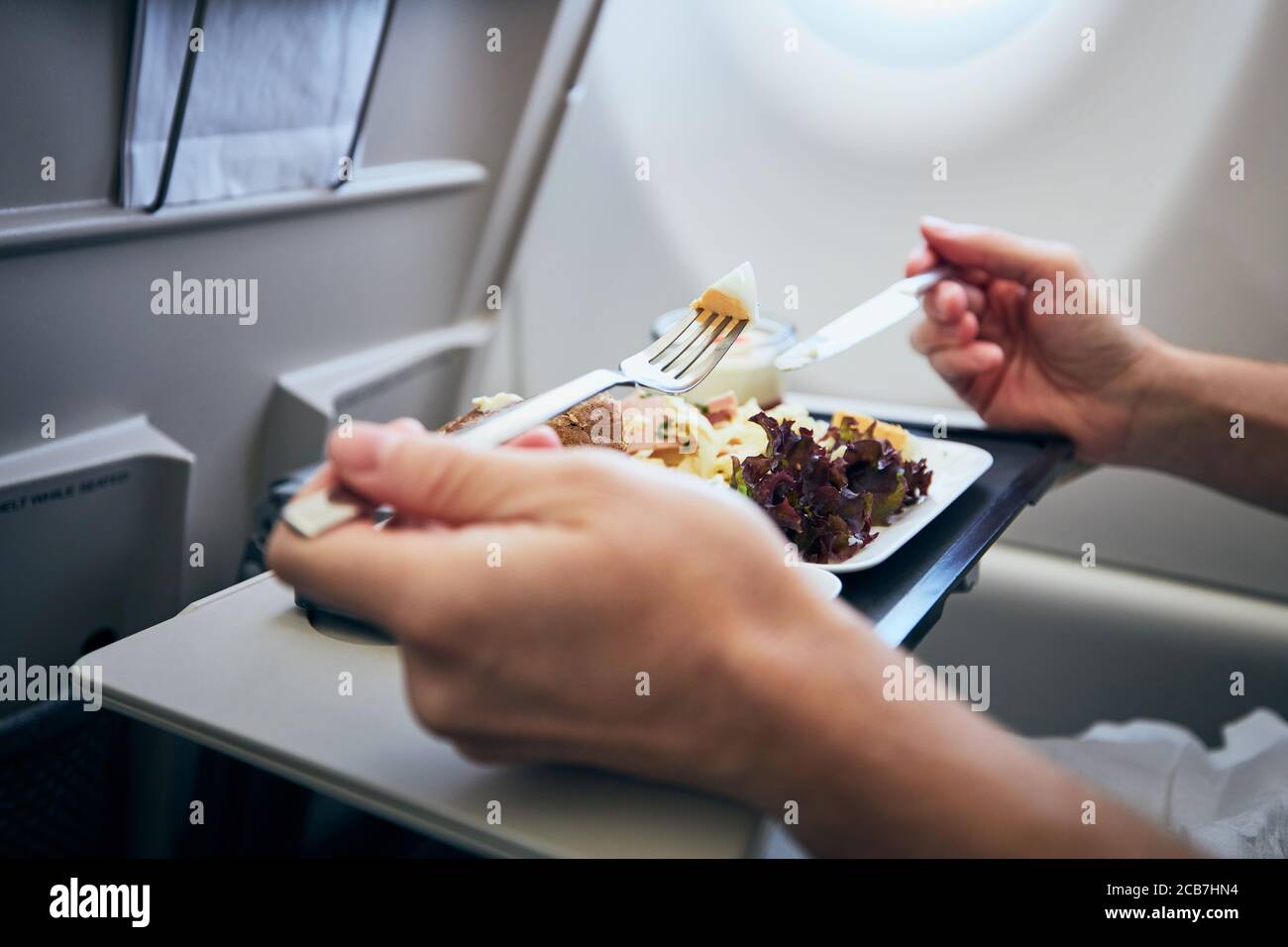 Man eating airline meal served on seat tables during flight Stock Photo ...