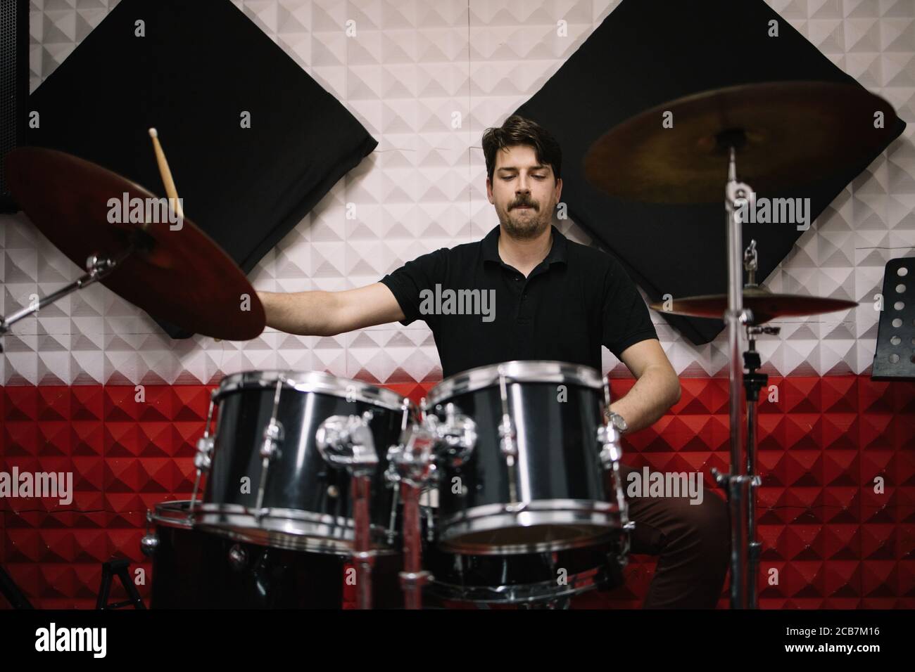 Man performer with drumsticks playing drums and cymbals. Adult man with ...