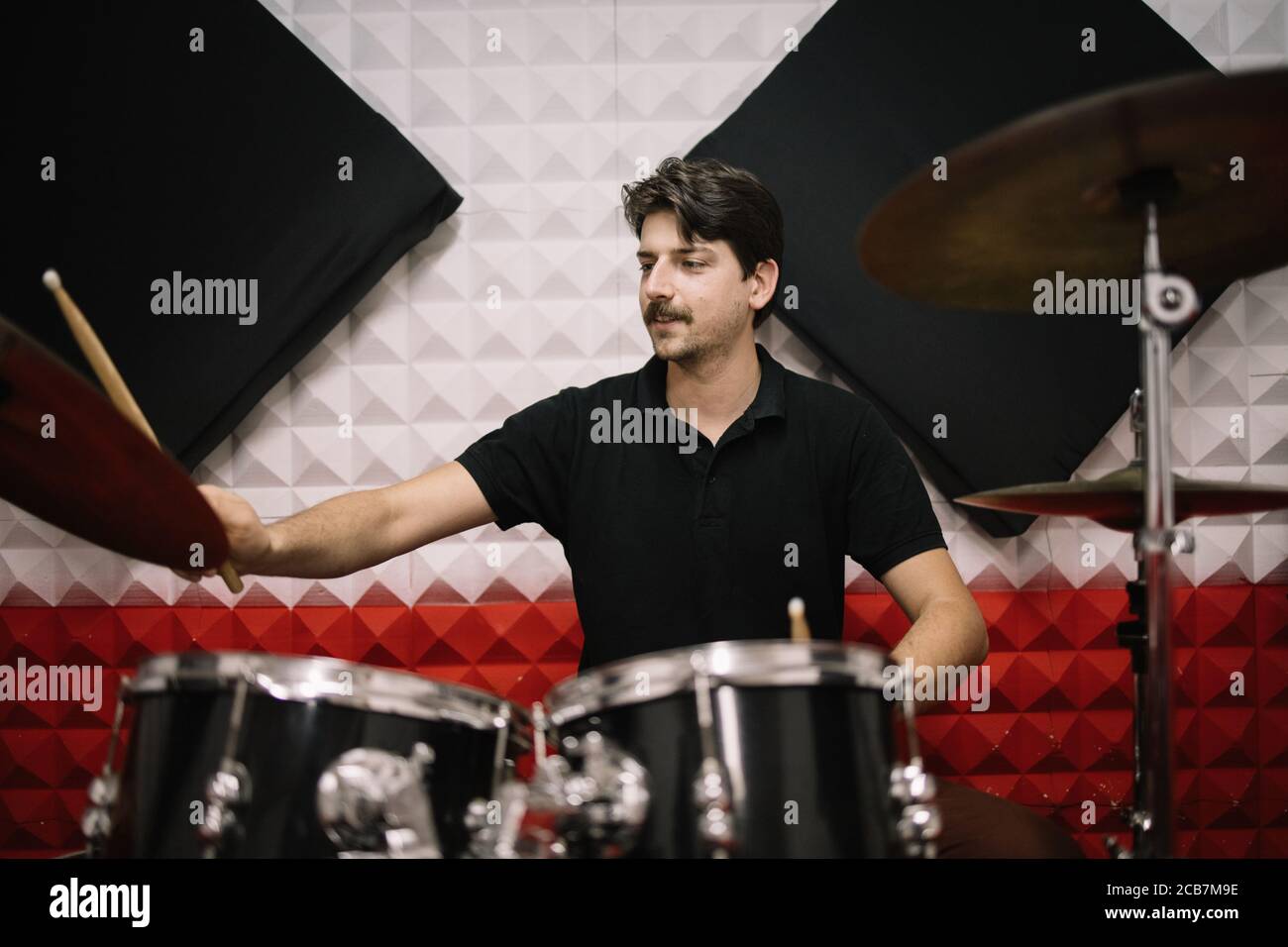Handsome man playing with drumsticks sitting at drums. Male performer ...