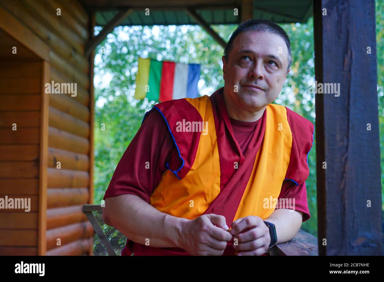 monk lama stands on the porch and holds a wooden rosary in his hand. He ...