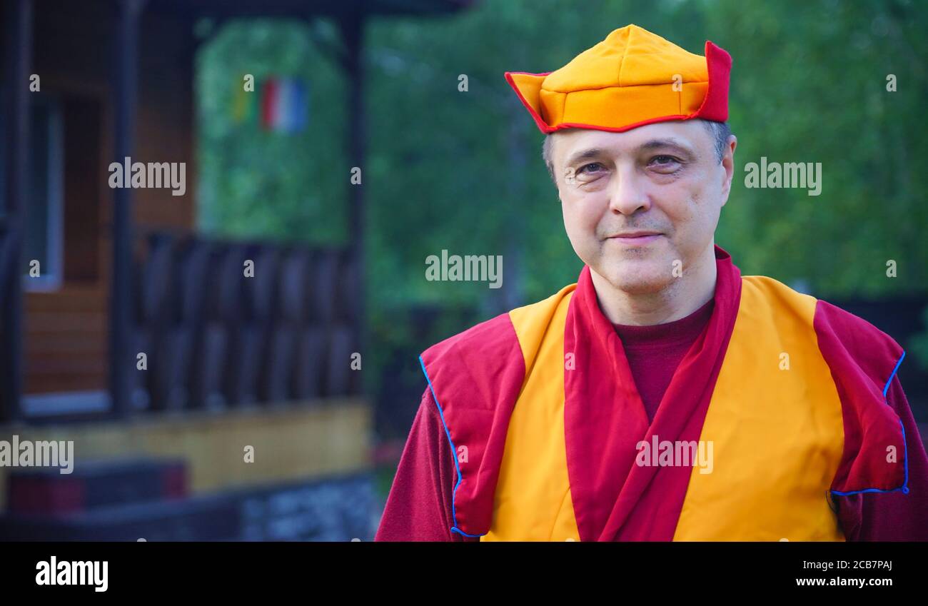 portrait of a monk in red clothes and a hat Stock Photo - Alamy