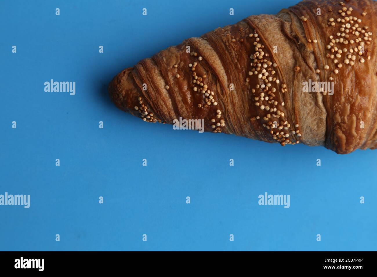 Closeup shot of a croissant on a blue table Stock Photo - Alamy