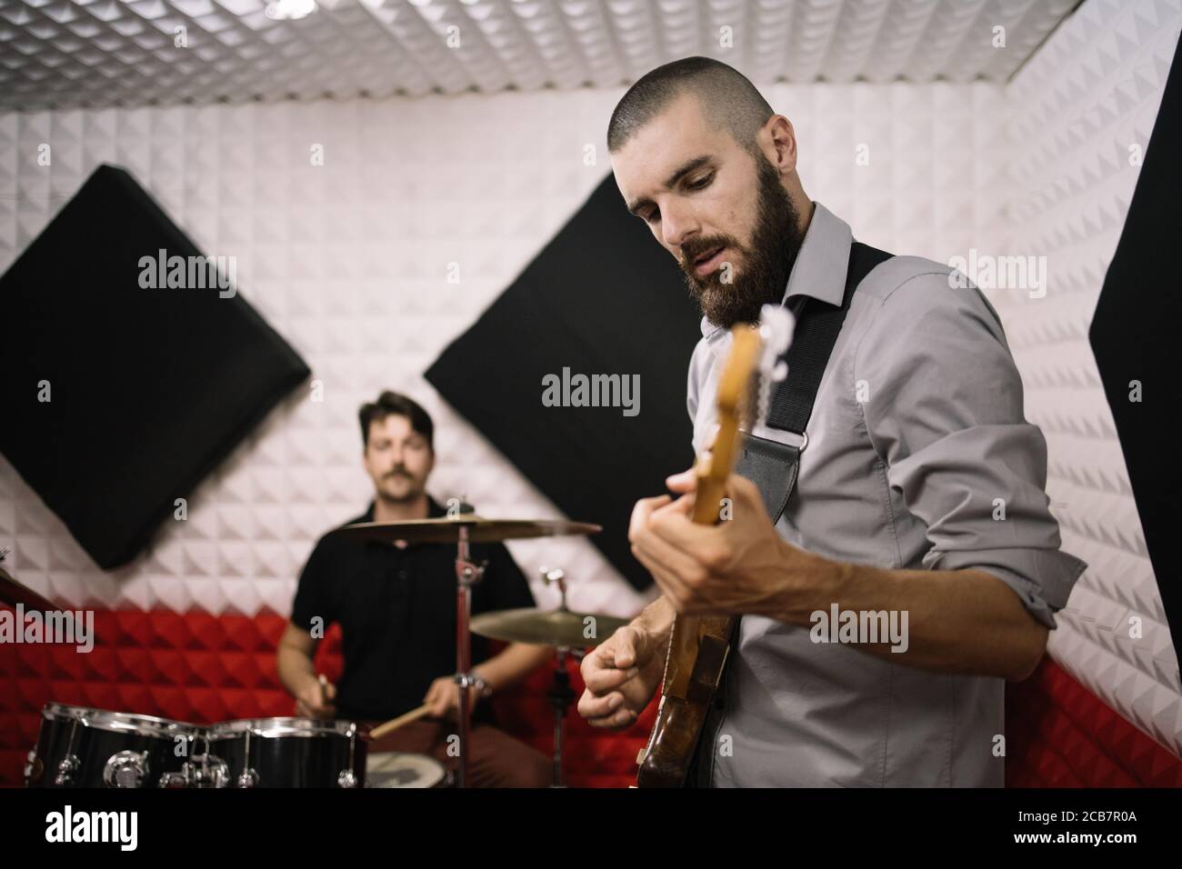 Two band members playing electric guitar and drum set Stock Photo - Alamy