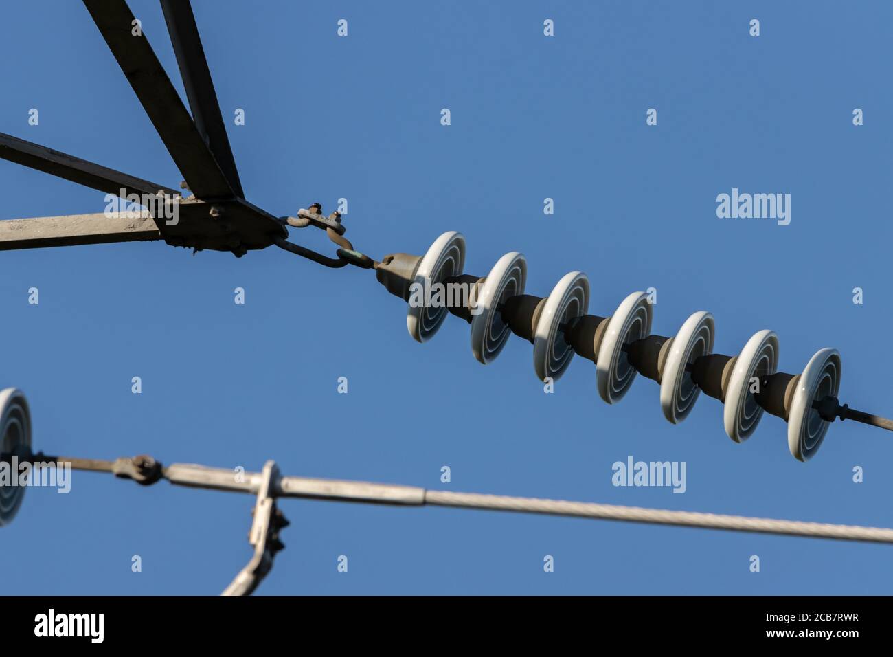 Powerline insulator with steel hydro tower and blue skies in background ...