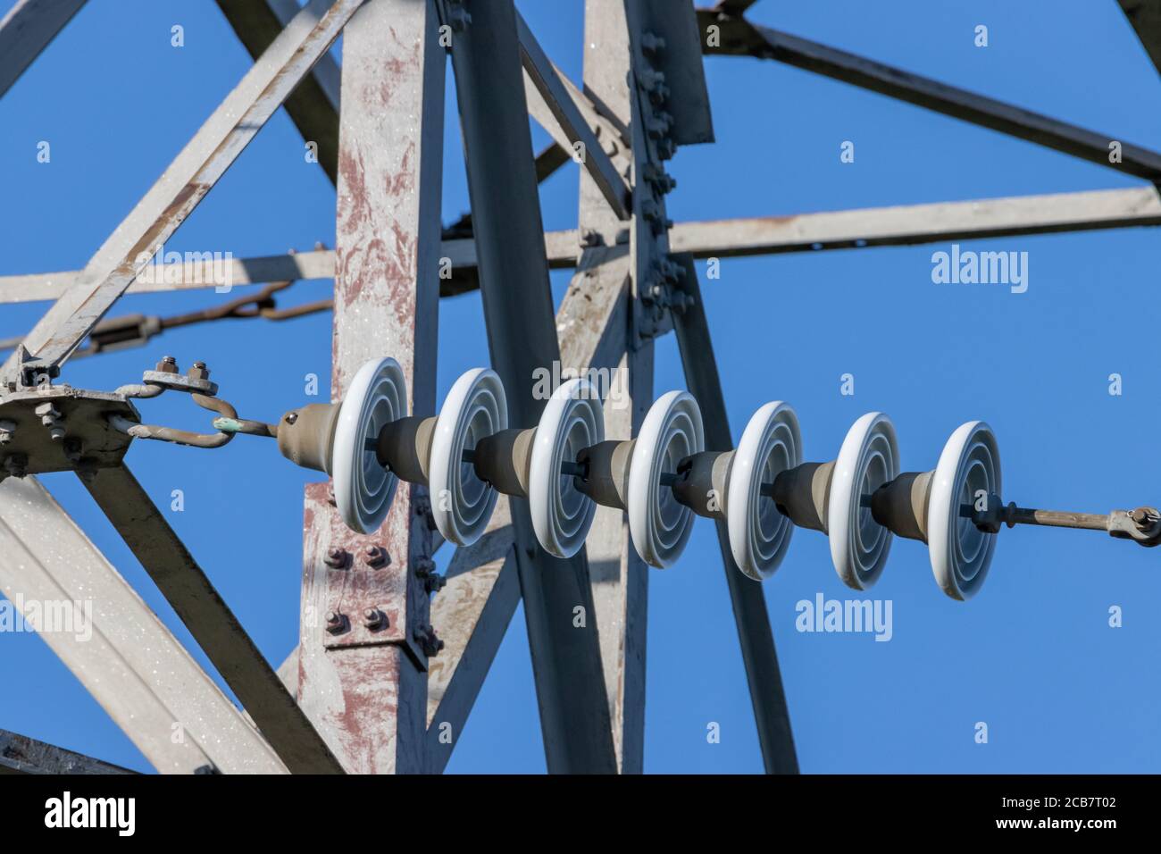 Powerline insulator with steel hydro tower and blue skies in background ...