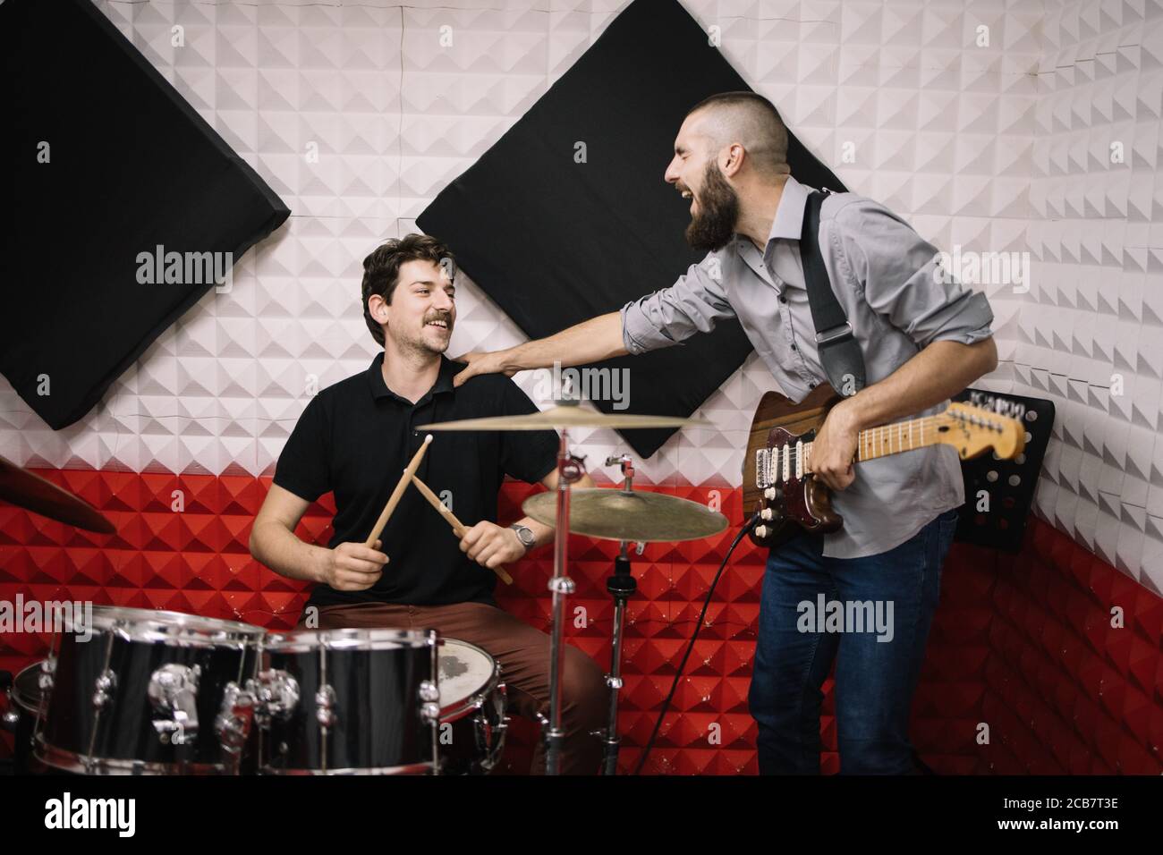 Band members laughing while standing in music recording studio Stock ...