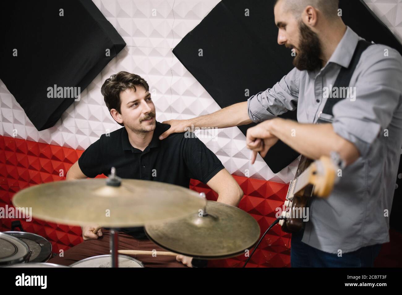 Drummer sitting behind drum set while speaking with guitar player Stock ...
