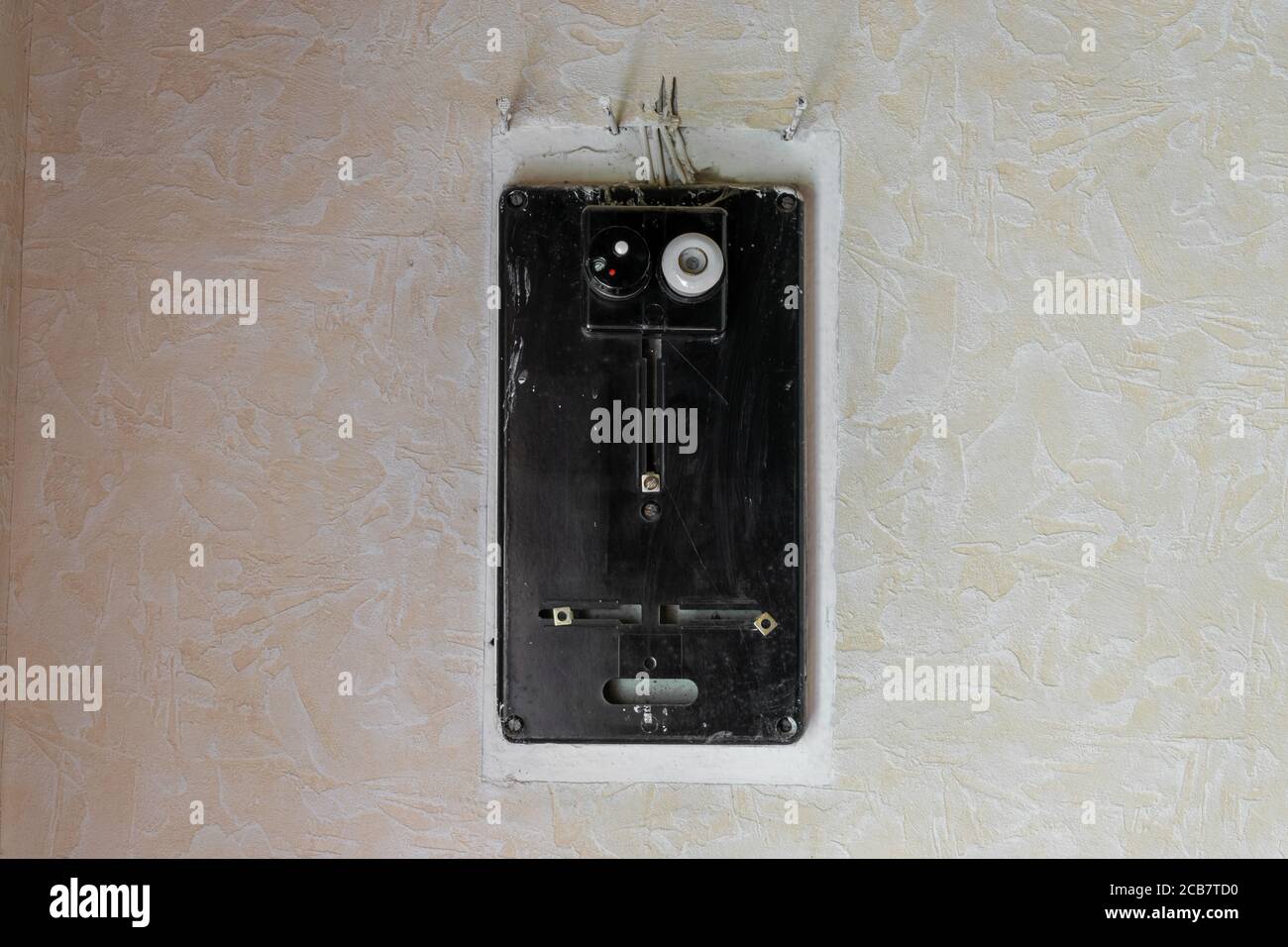 Very old black electrical fuses box hanging on white rural wall with ...