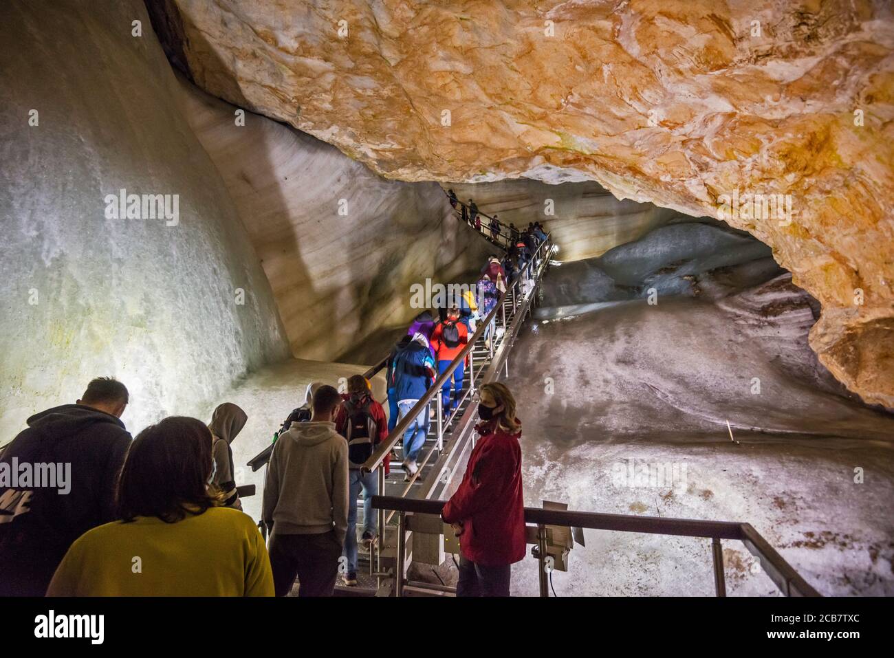 Visitors at walkway between rock and ice formations, Dobsinska Ice Cave ...