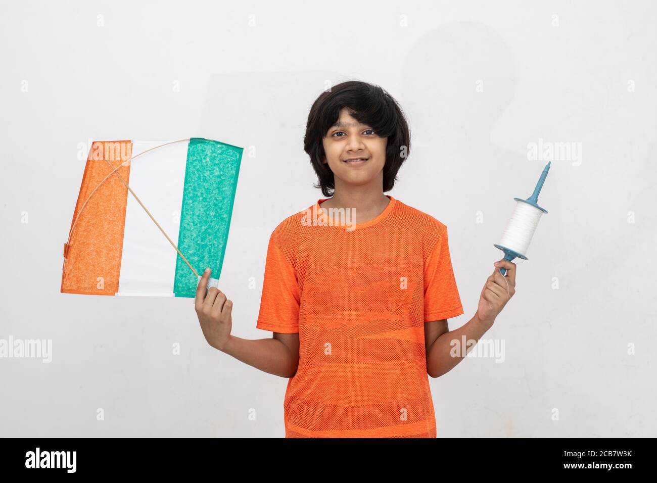 Young Indian boy holds onto a a spool of thread and a Kite with the ...
