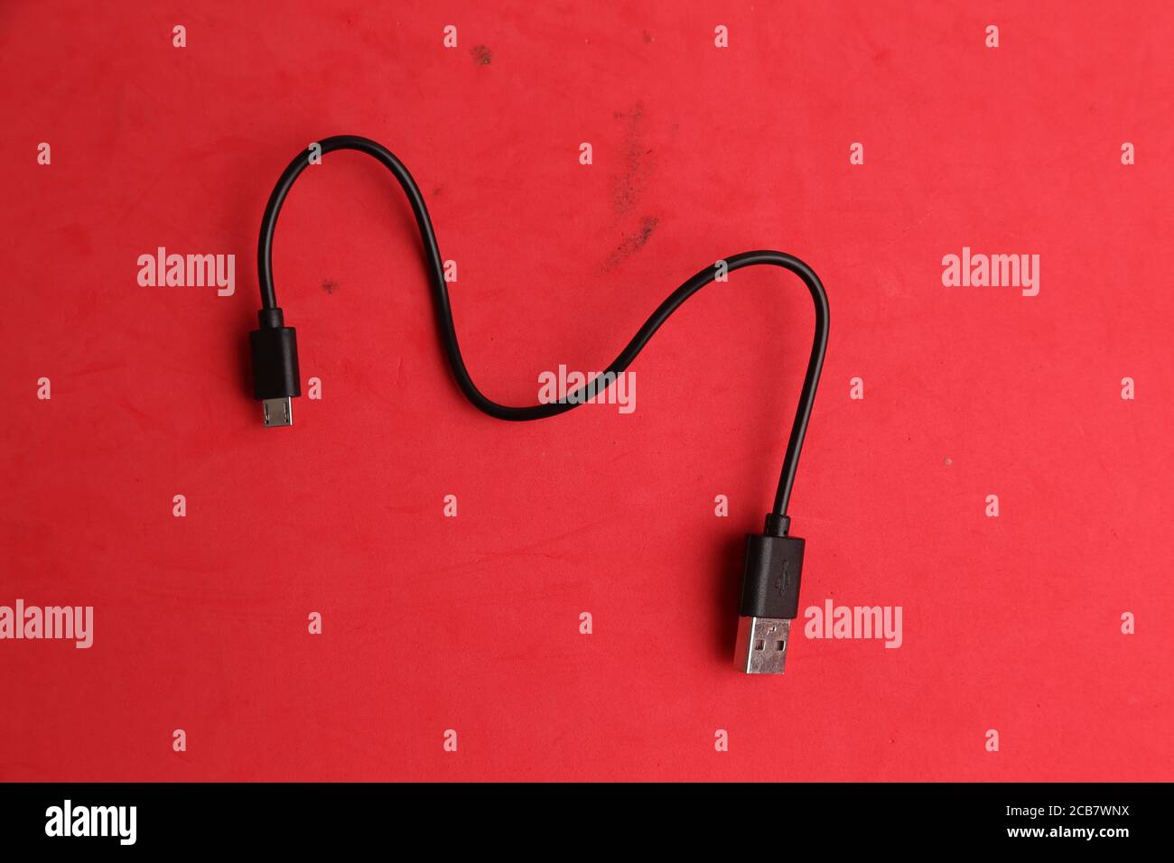 Black USB cable on a red surface Stock Photo - Alamy