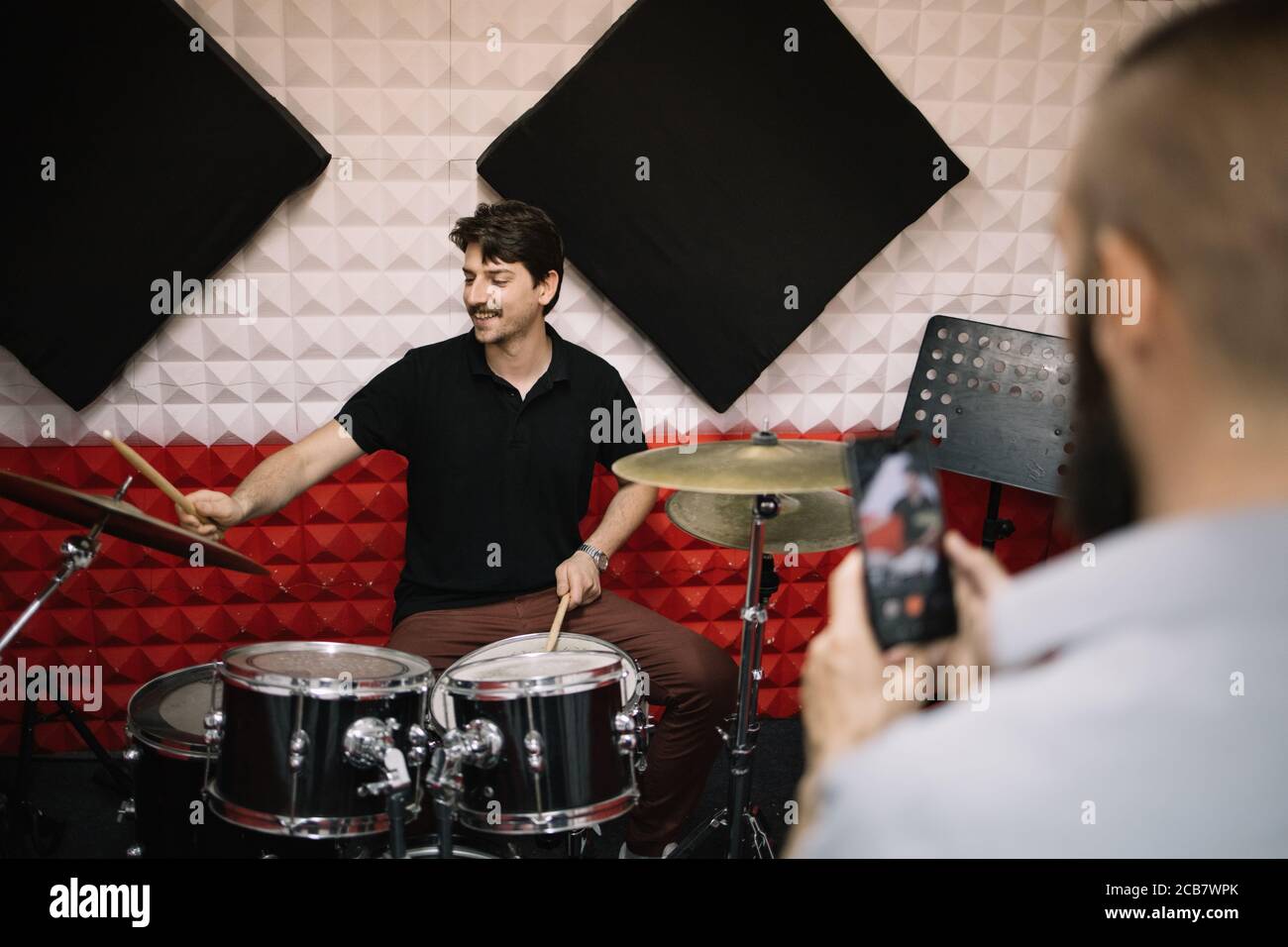 Out of focus man is taking pictures of happy drummer Stock Photo - Alamy