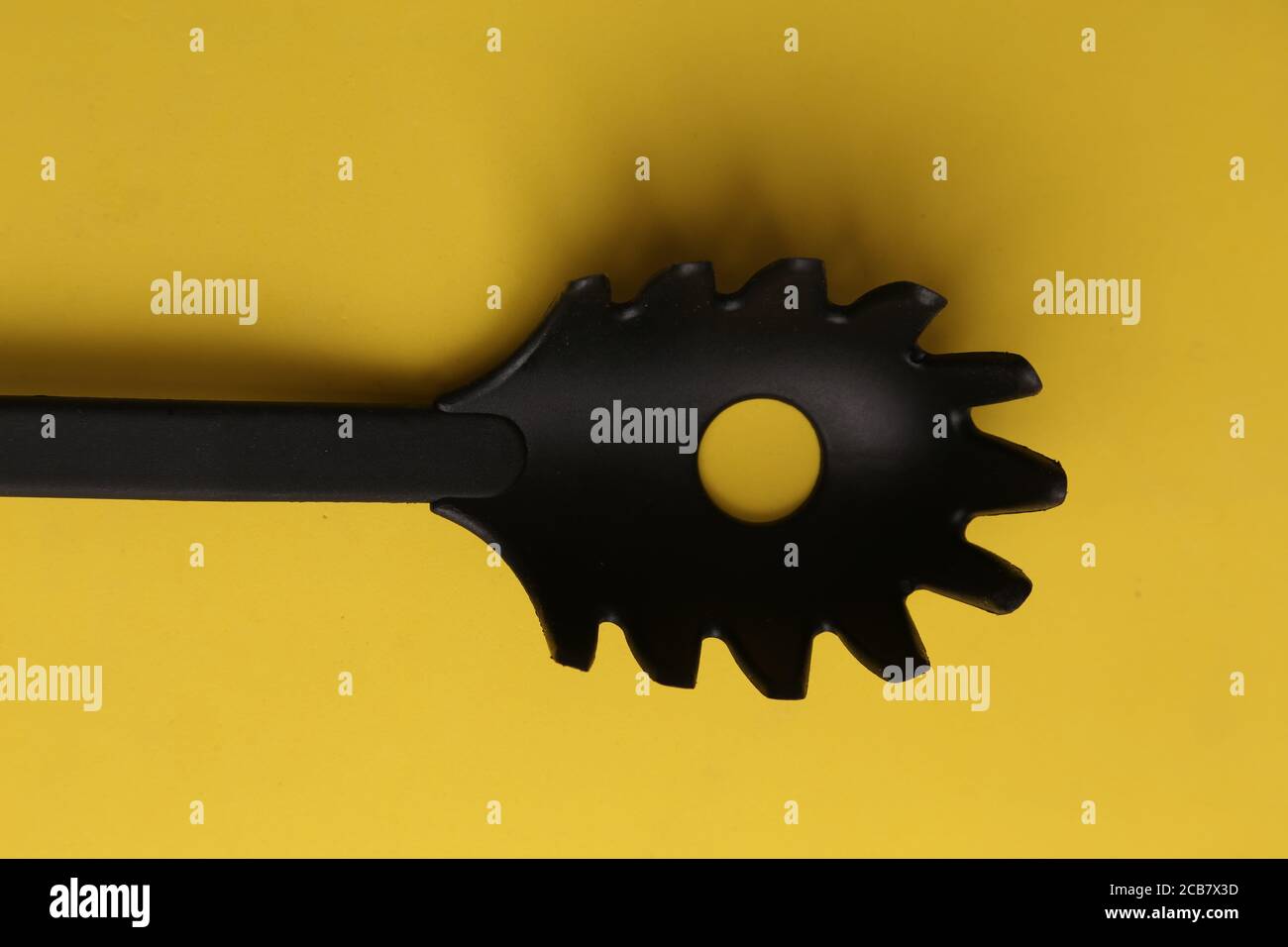 High angle closeup shot of a spaghetti spoon on a yellow background ...