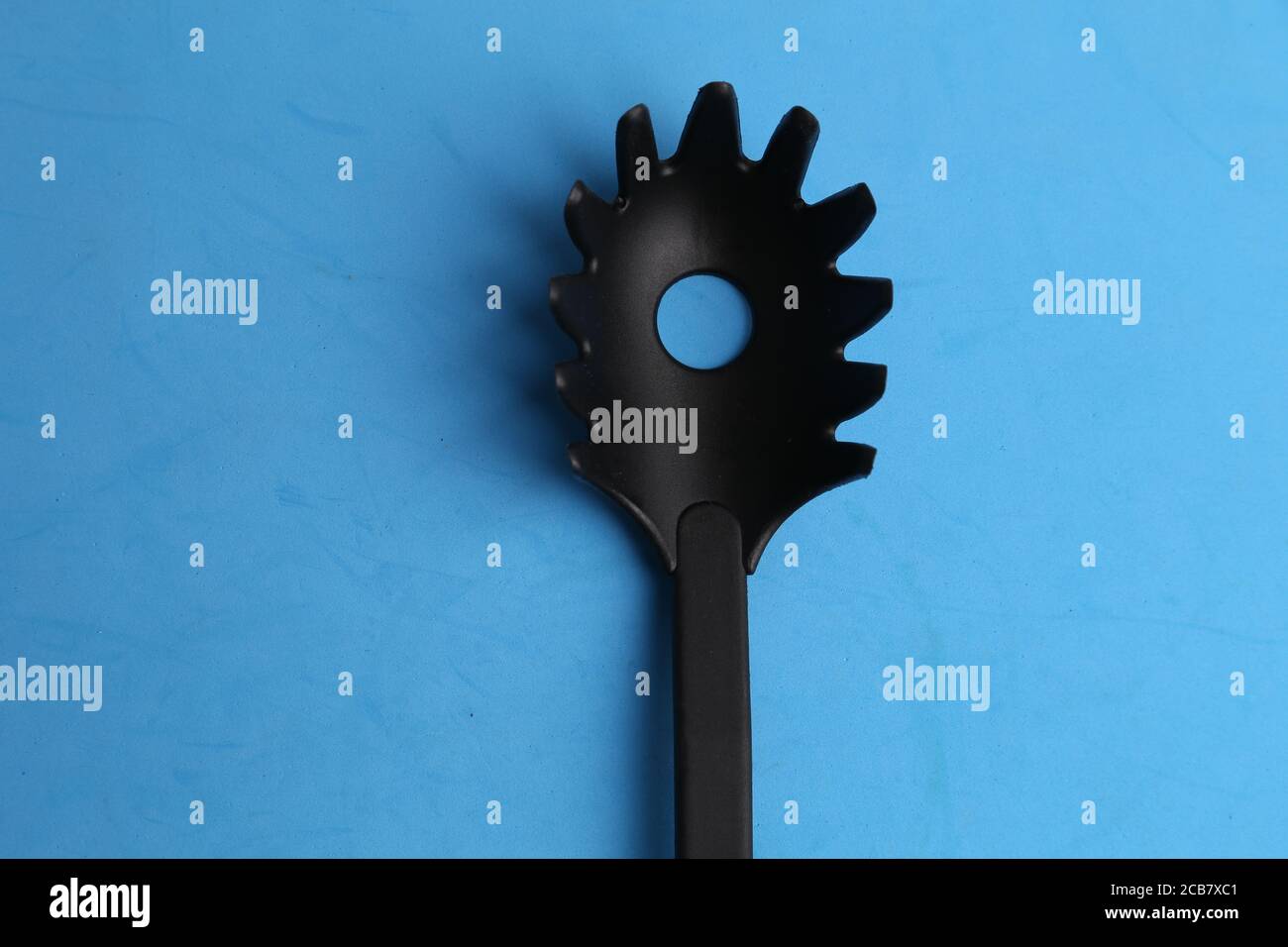 Black spaghetti spoon on blue background Stock Photo - Alamy