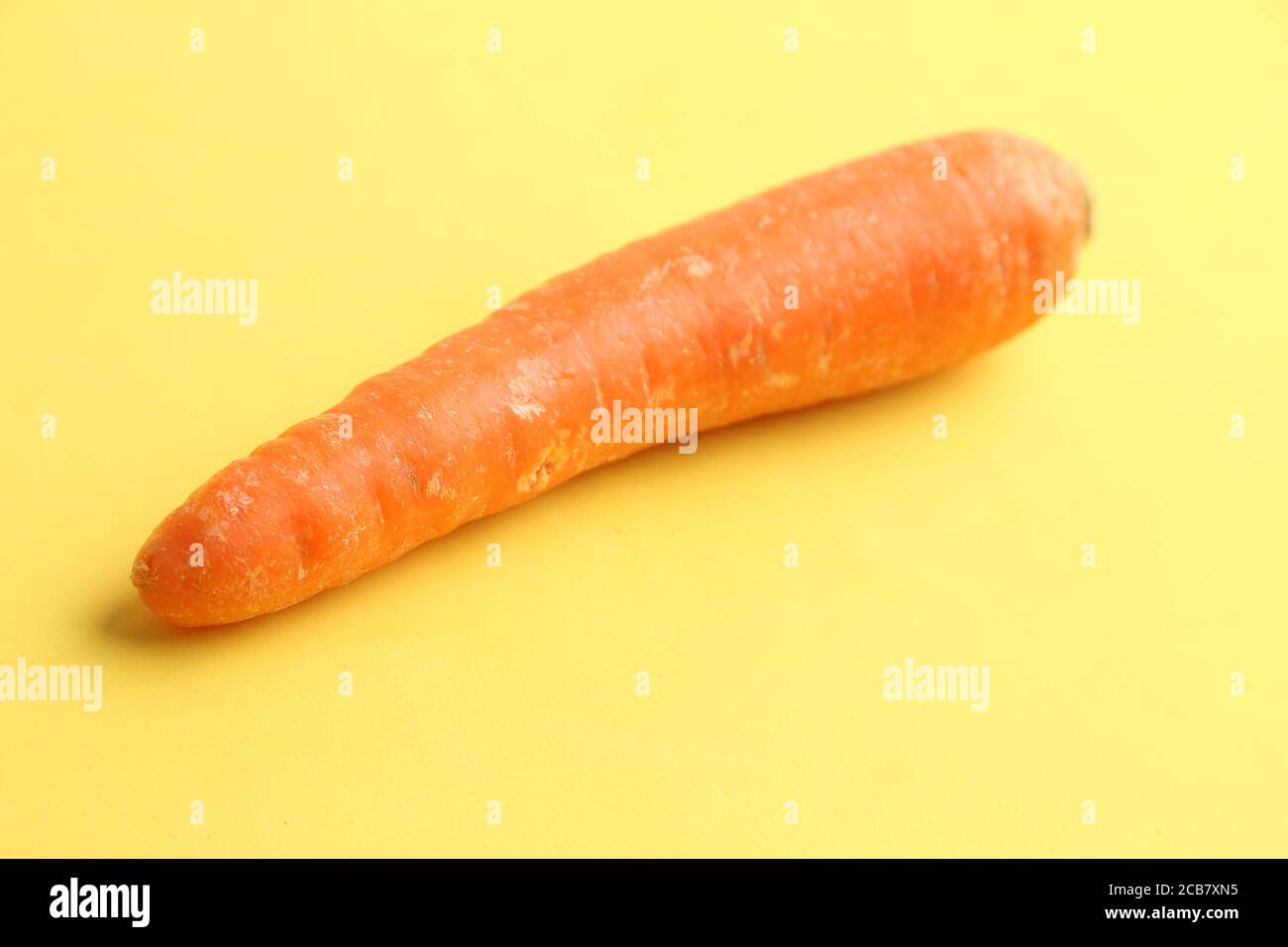 Raw carrot on a yellow surface Stock Photo - Alamy