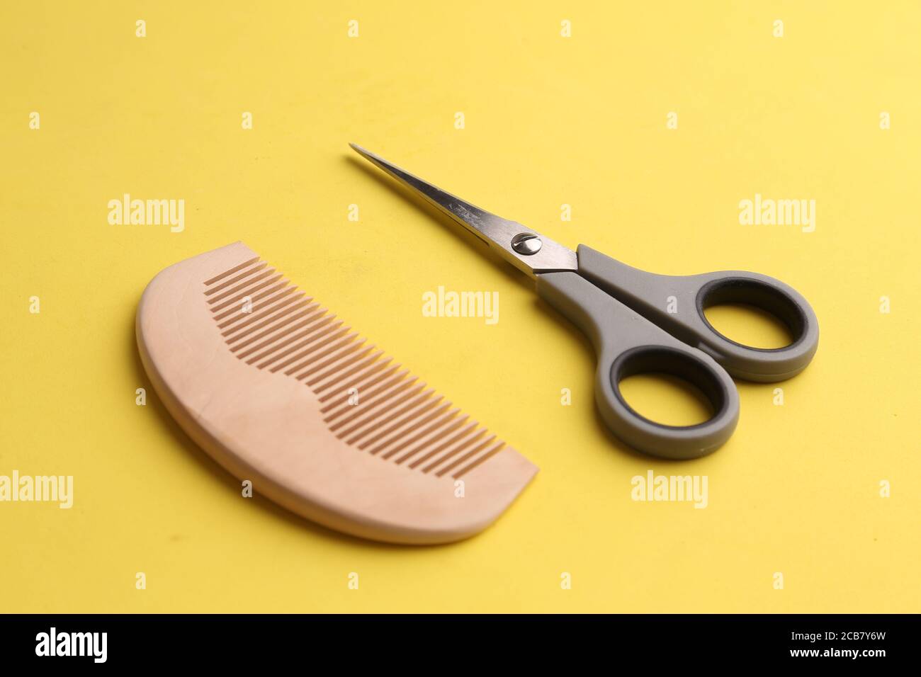 Wooden hairbrush and scissors for a hairdresser on a yellow background ...