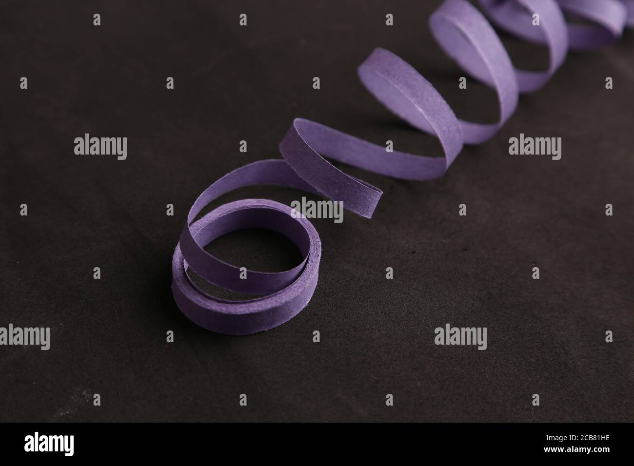 Purple party streamer isolated on a black background Stock Photo - Alamy