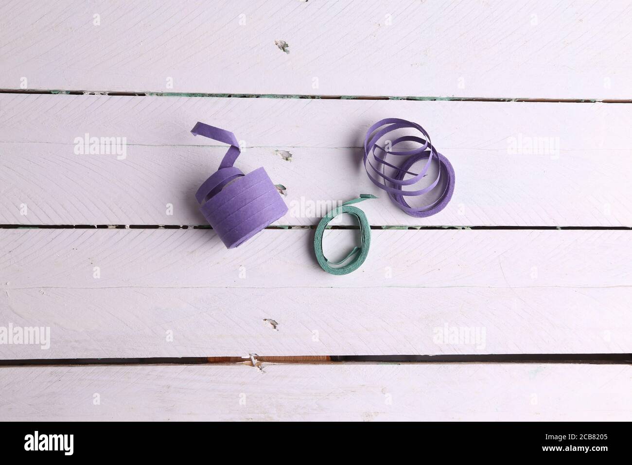Top view of green and purple party streamers on a white wooden table ...