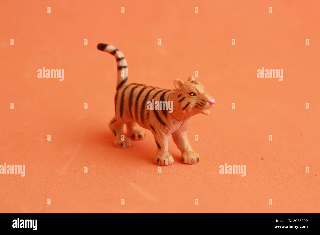 Small rubber tiger toy isolated on an orange background Stock Photo - Alamy