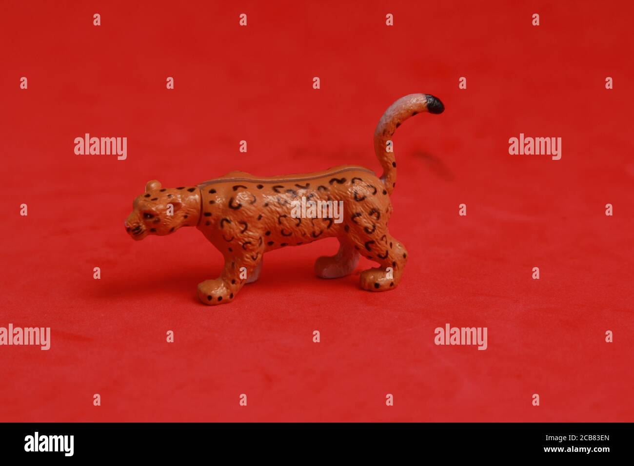 Small leopard toy on a red surface Stock Photo - Alamy
