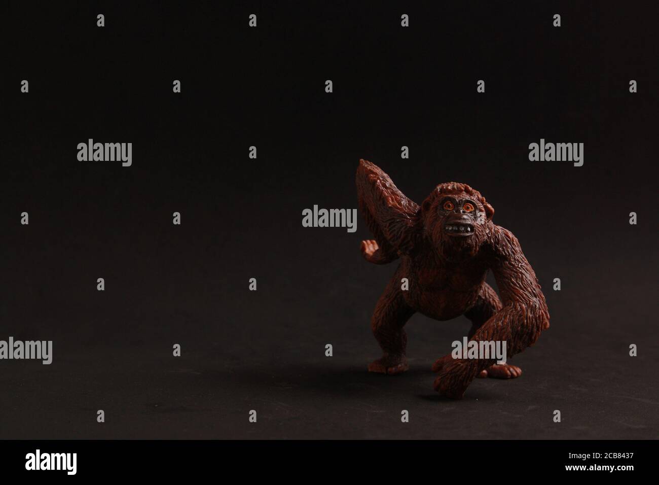Small rubber ape toy isolated on a black background Stock Photo - Alamy