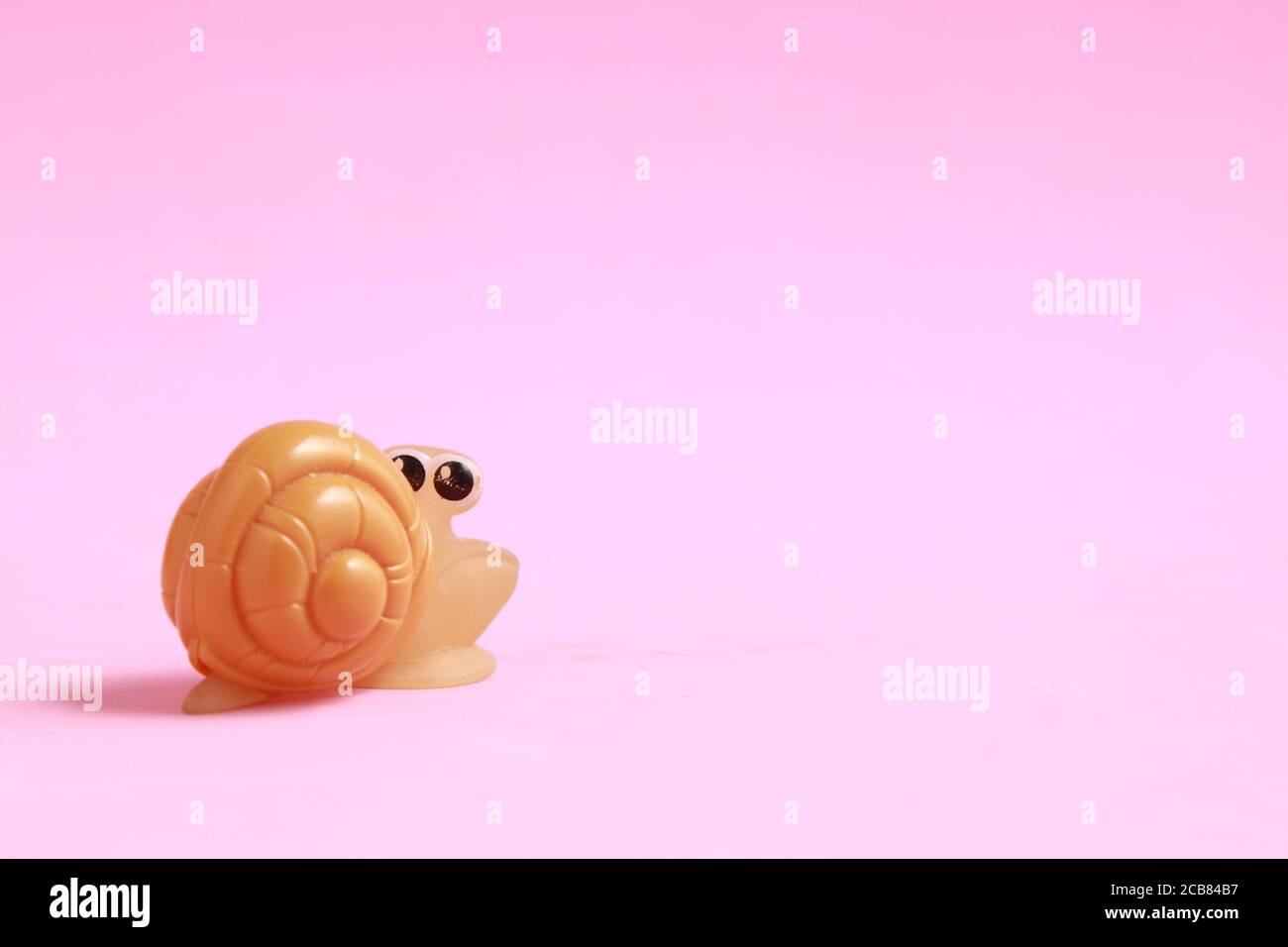 Small rubber snail toy on a pink background Stock Photo - Alamy