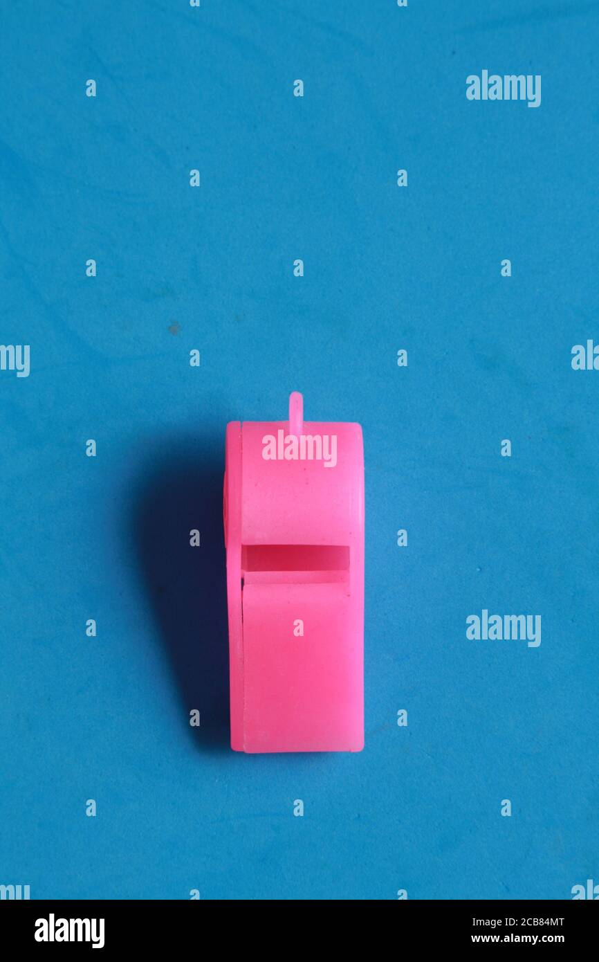 Top view of a pink plastic whistle on a blue background Stock Photo - Alamy