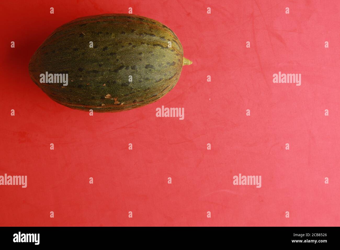 Isolated high angle top view closeup shot of a melon on a red table ...