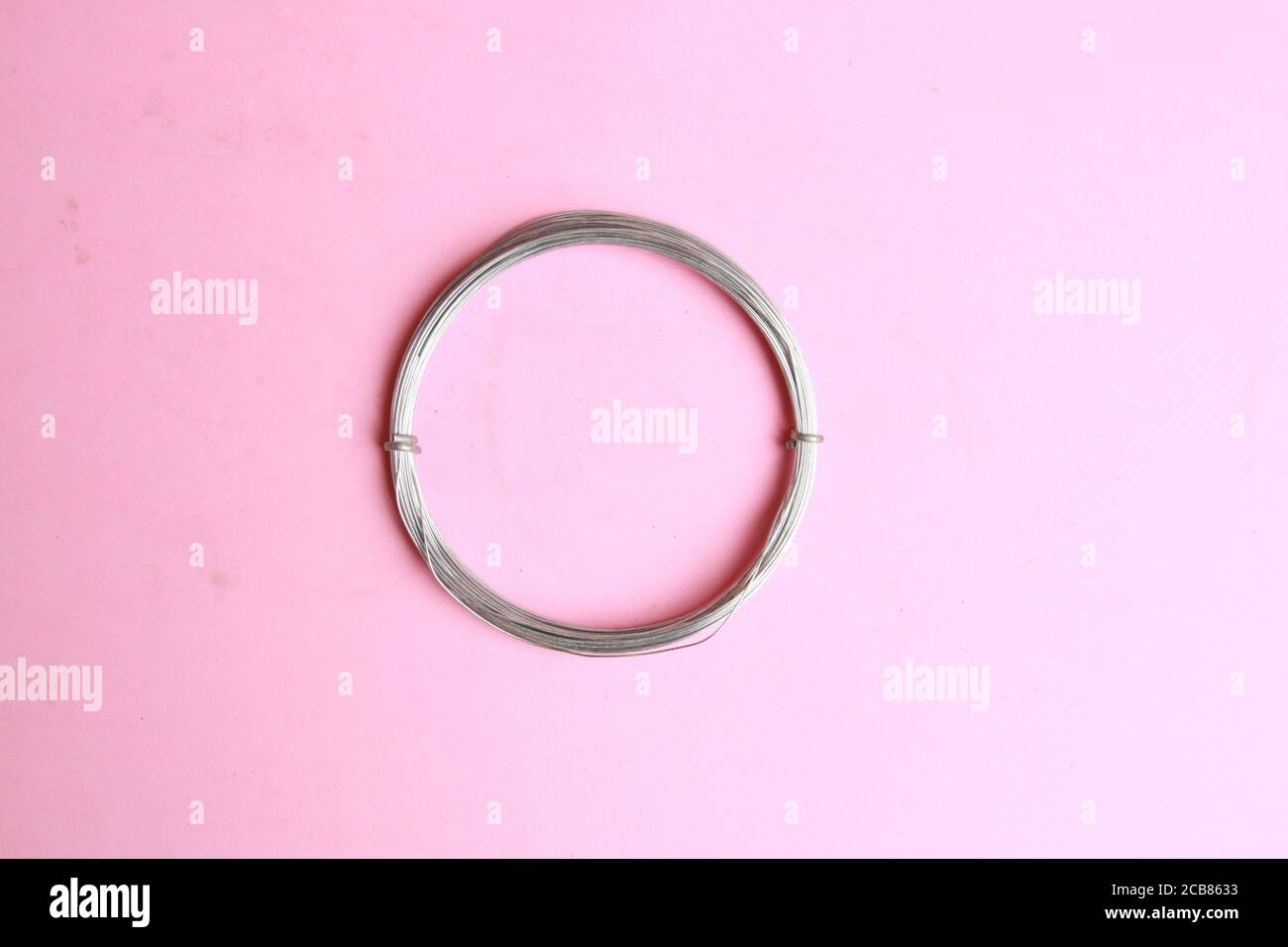 Roll of metal wire against a pink background Stock Photo - Alamy