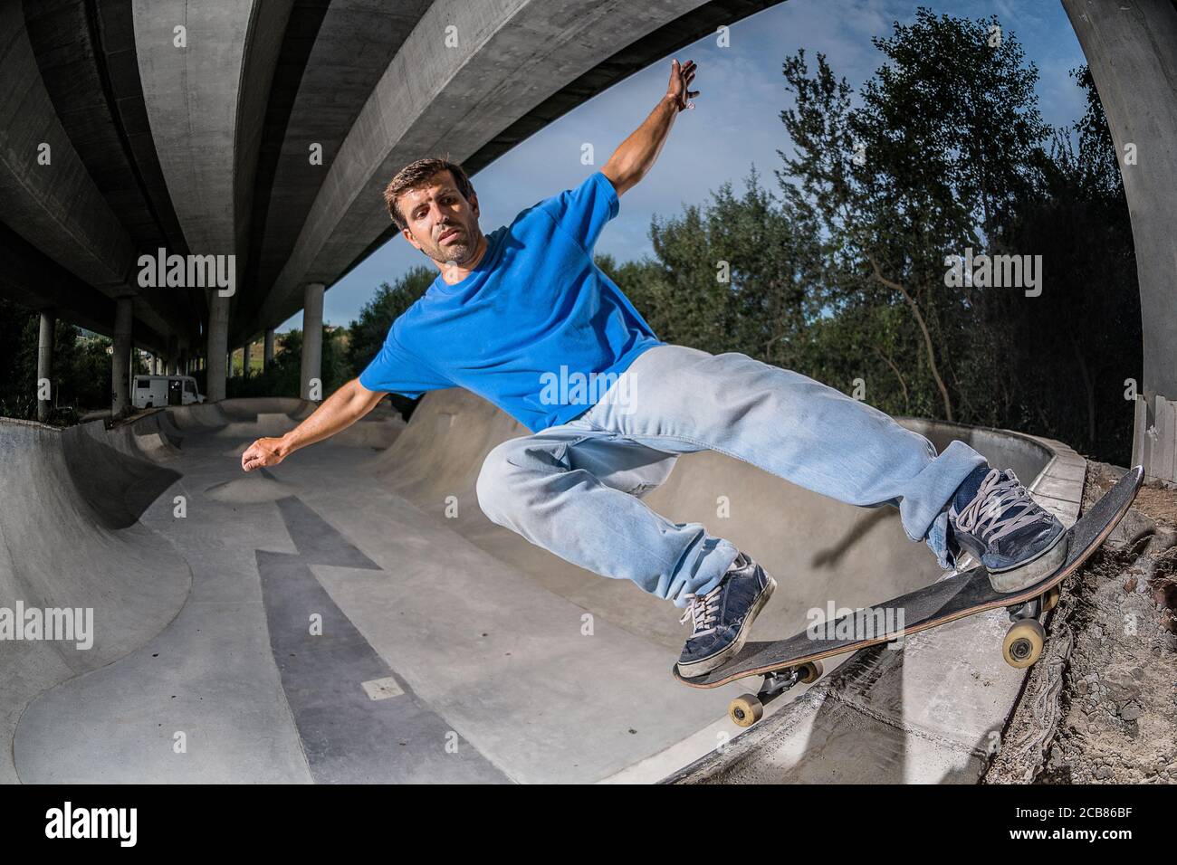 Skateboarder in a concrete skatepark under a highway bridge Stock Photo ...