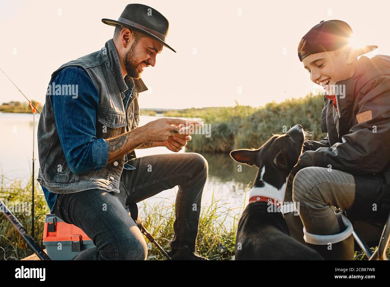 Teen boy and father have lunch. They caught fish. Now they sit and ...