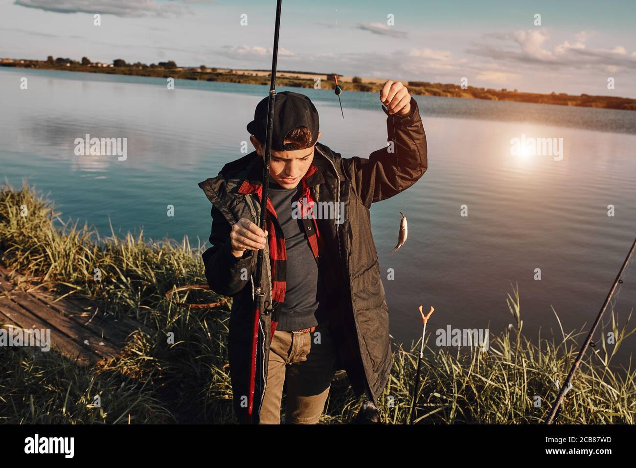 Teen caucasian boy caught first fish. He hold fishing rod and fish ...