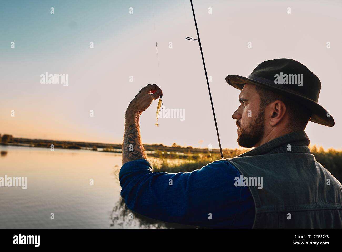 Caucasian bearded man holds bait for fish and checks it. background ...