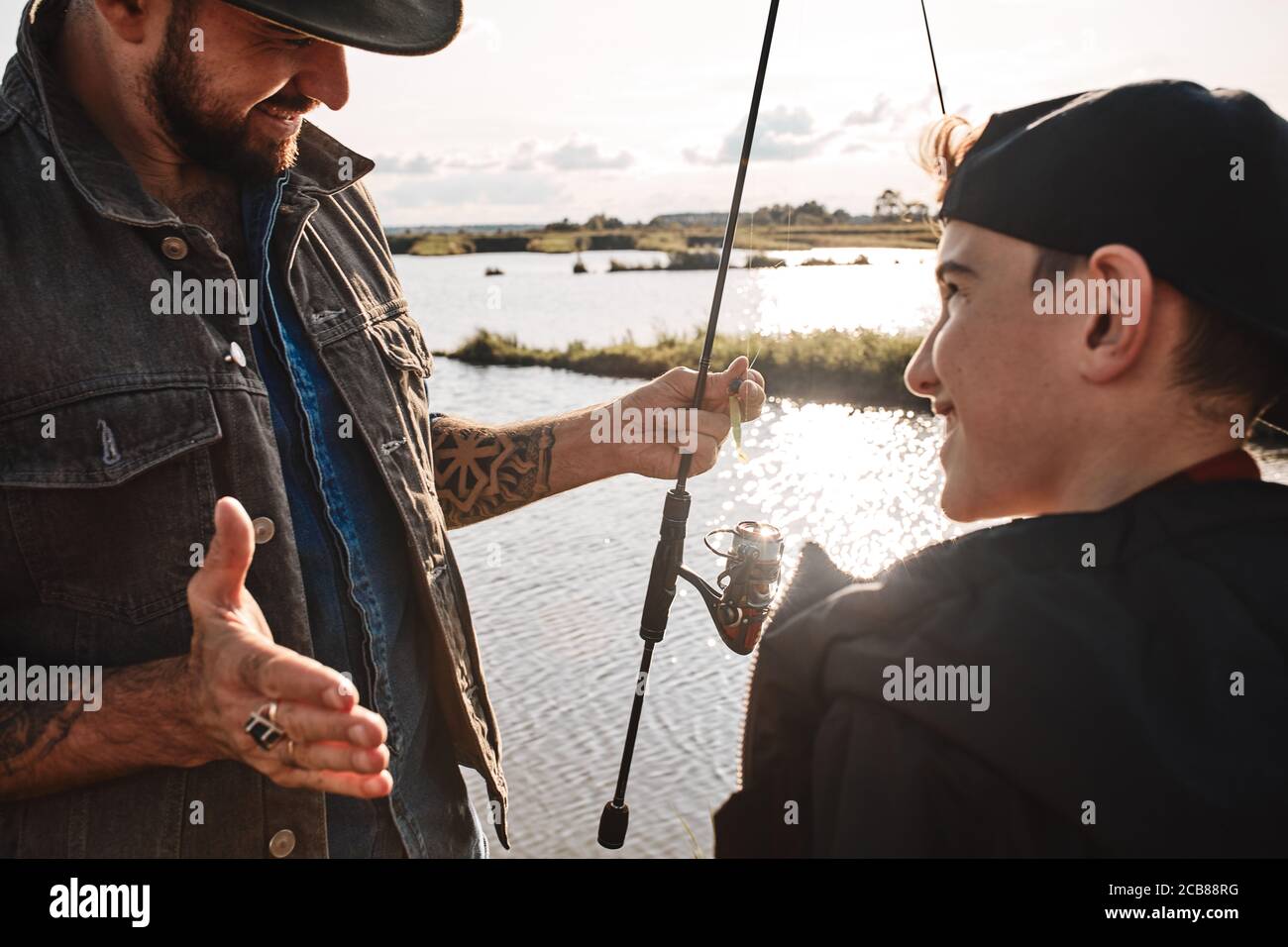 Adult father shows fishing rods as example how use hooks and fishing ...