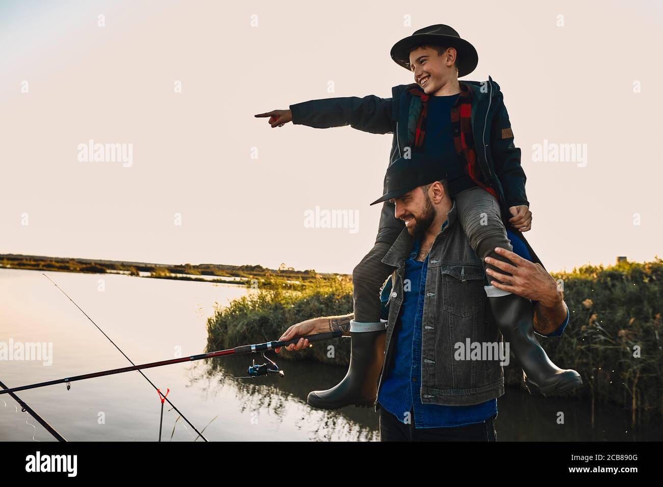 Father and son have fun while fishing. Teen boy happy and smile, sit on ...