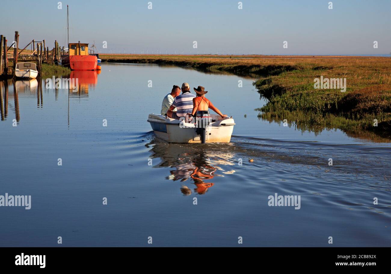 A small dinghy with three people on board setting off on a boat trip at ...
