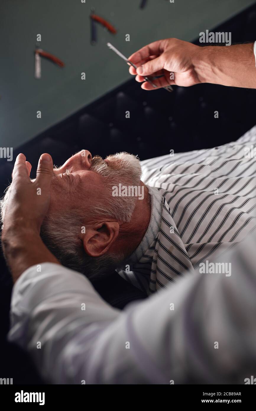 barber touching his client's head, going to kill old man, crime concept ...